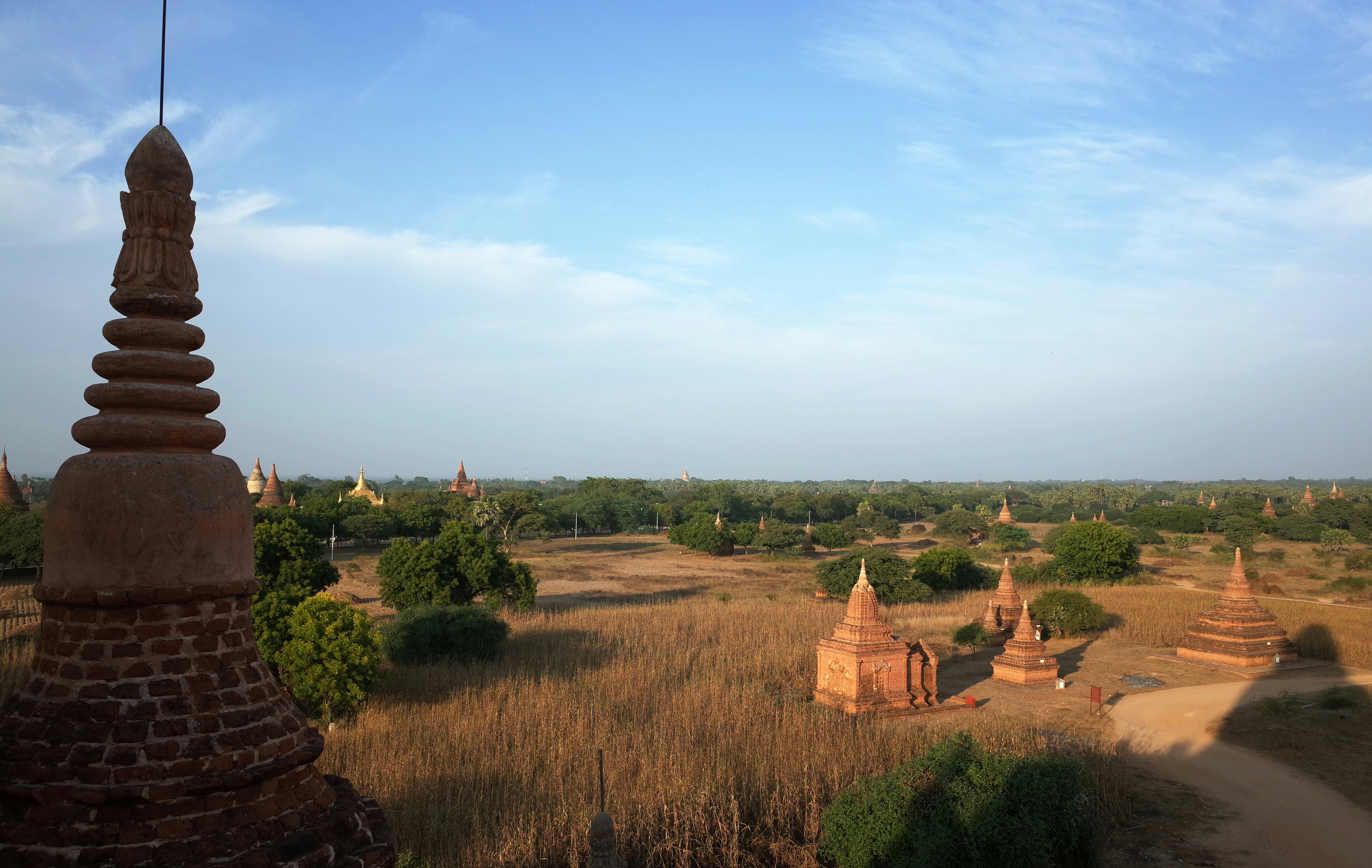 Brick pagodas scattered across a grassy plain under a bright blue sky.