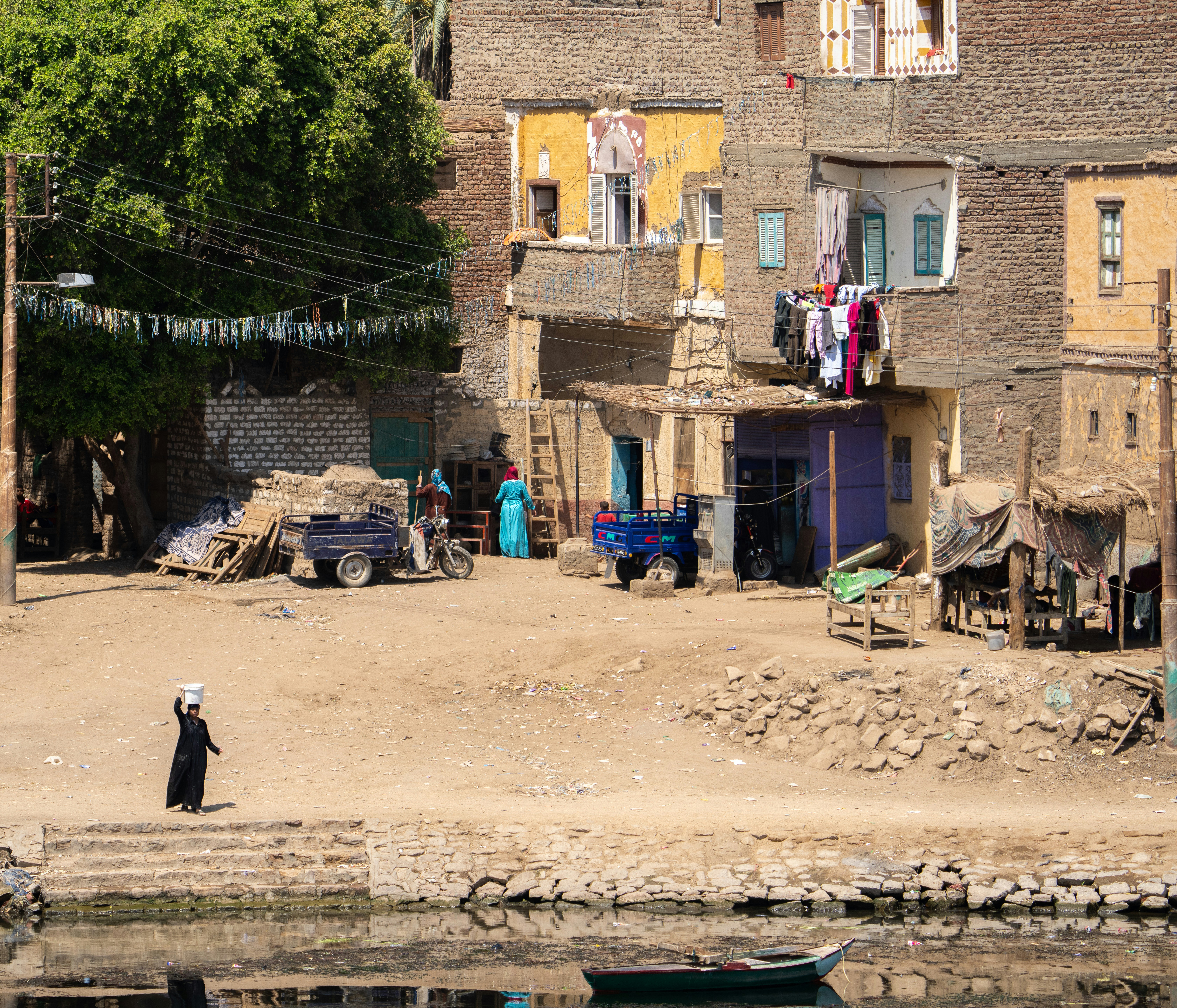 Solitary silhouette along a sunlit riverbank amid brick-and-cloth-lined homes