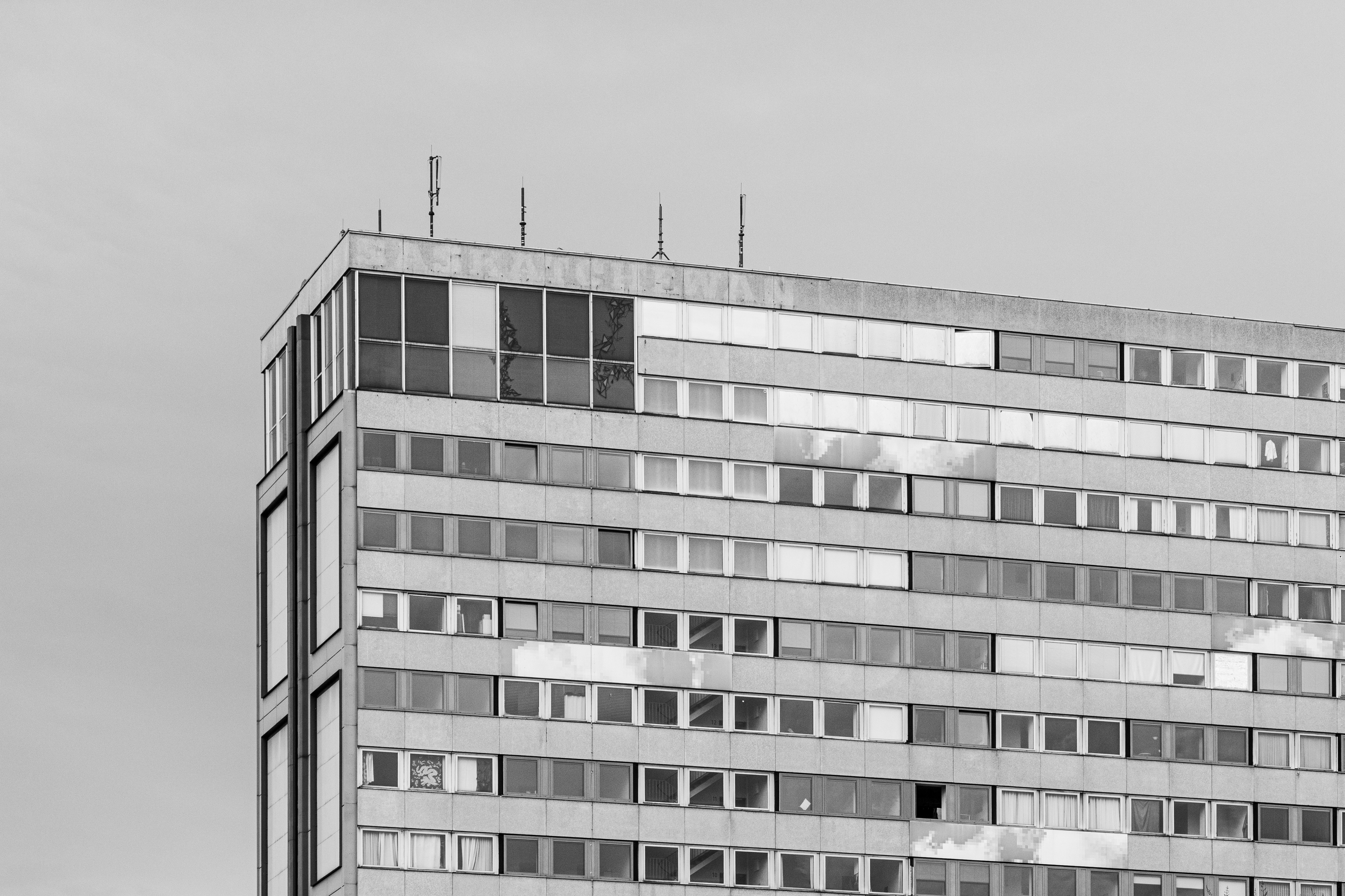 Monochrome depiction of a high-rise building showcasing its reflective glass facade and architectural lines. The image emphasizes the interplay of light and structure.