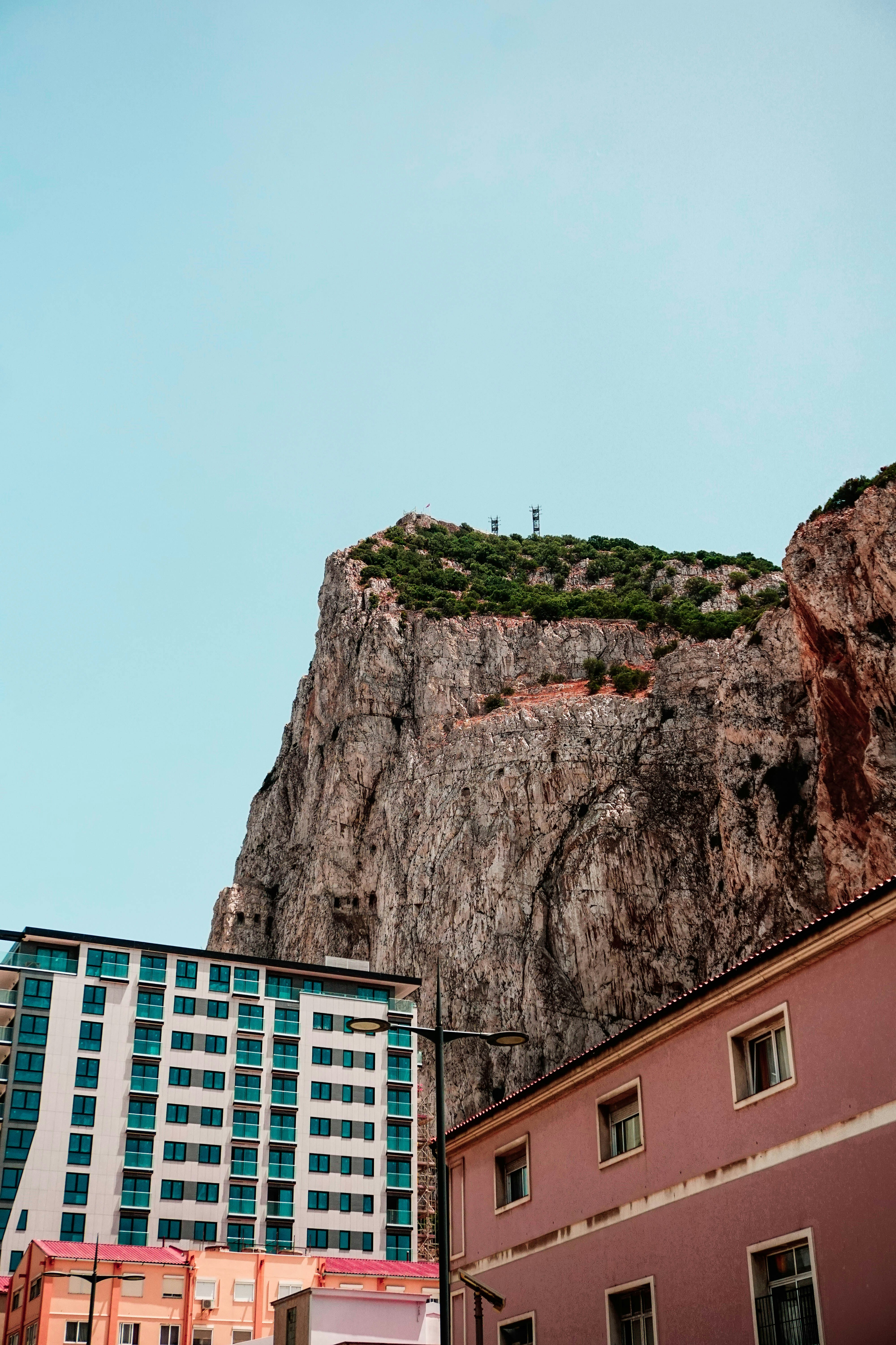 Cliffside Sentinel Over a Patchwork Cityscape: Stone, Sky, and Pastels