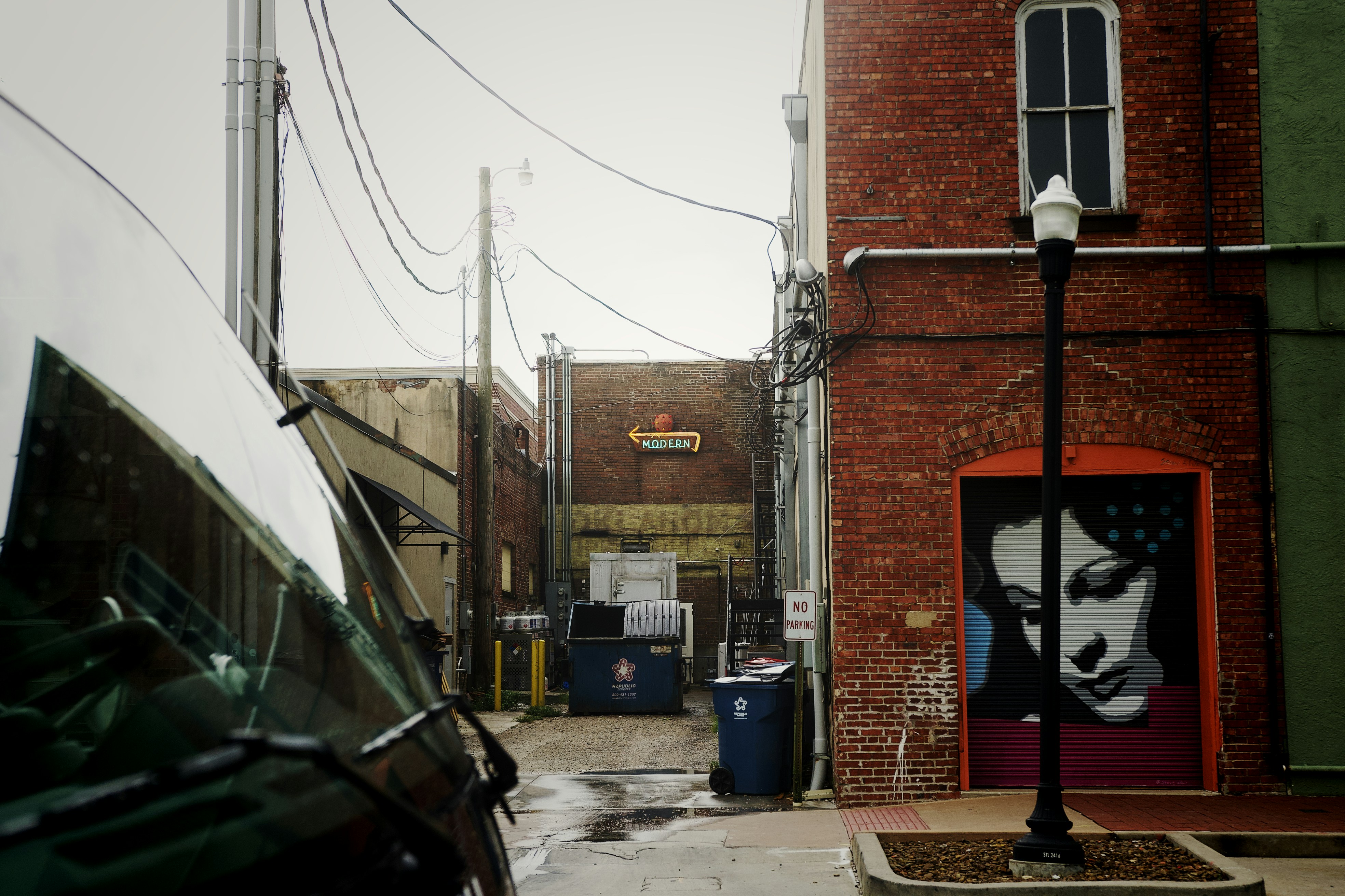 Urban Alleyway Echoes: A Graffiti Portrait Guards the Red Brick Gate