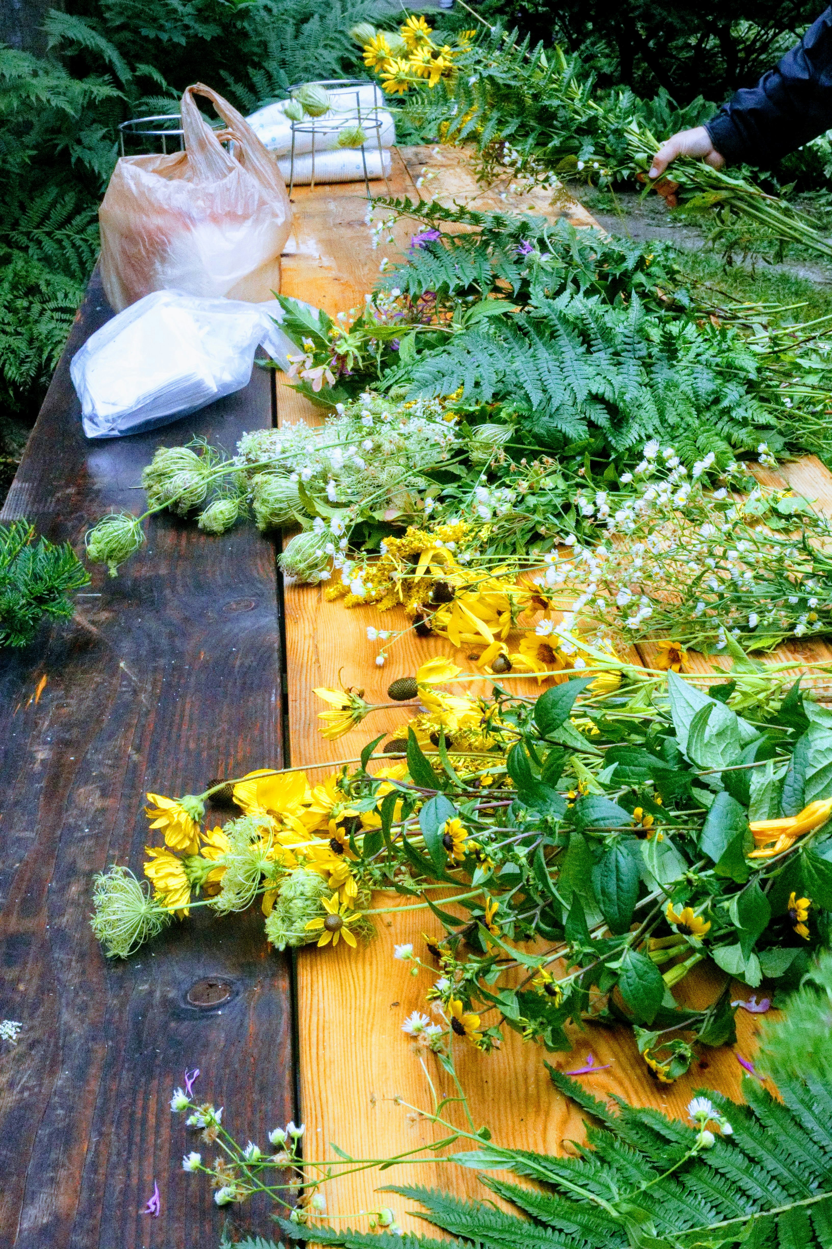 A vibrant assortment of wildflowers and greenery arranged on a wooden table, showcasing the beauty of nature's colors and textures.