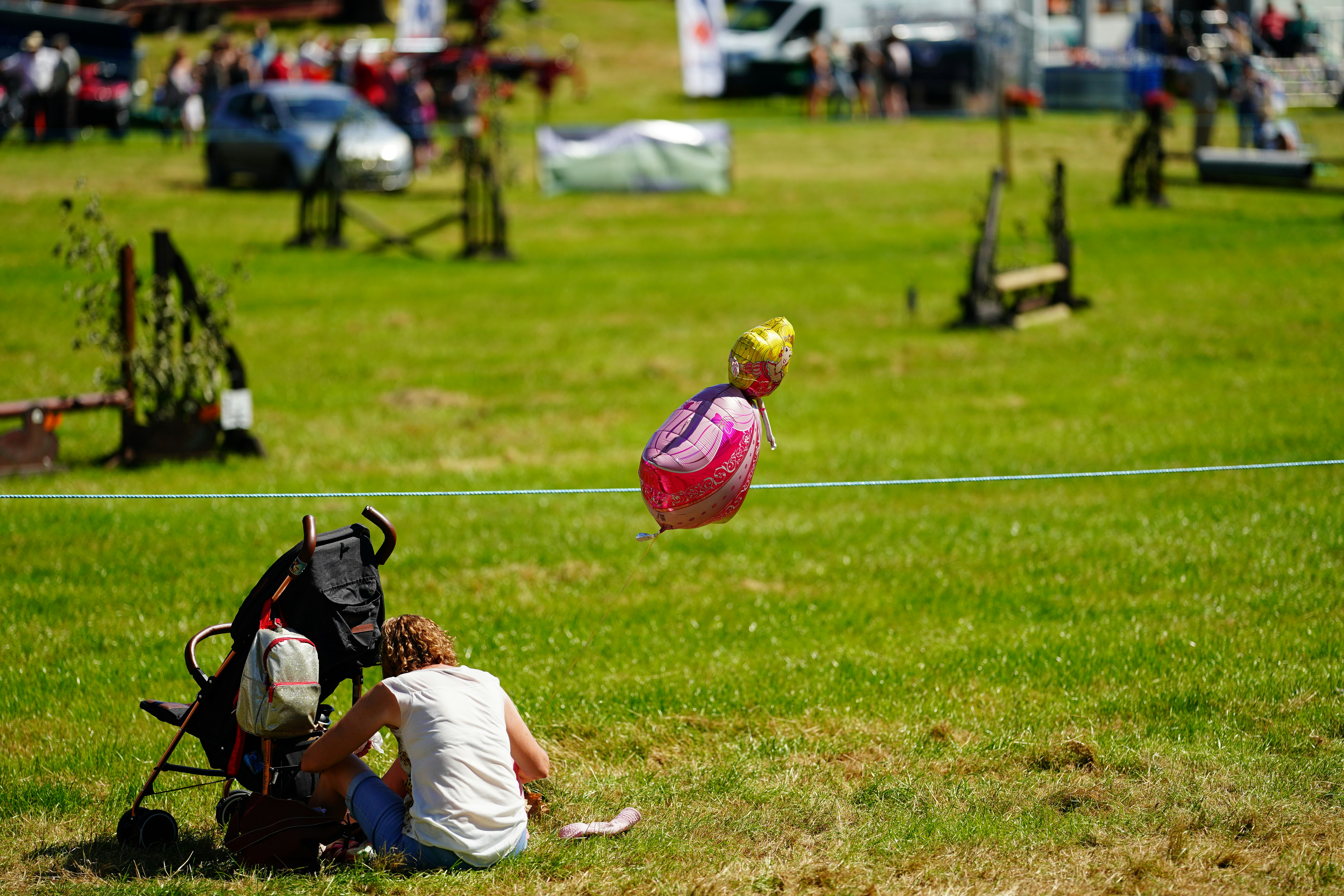 a person sitting on the grass with a balloon in the hand