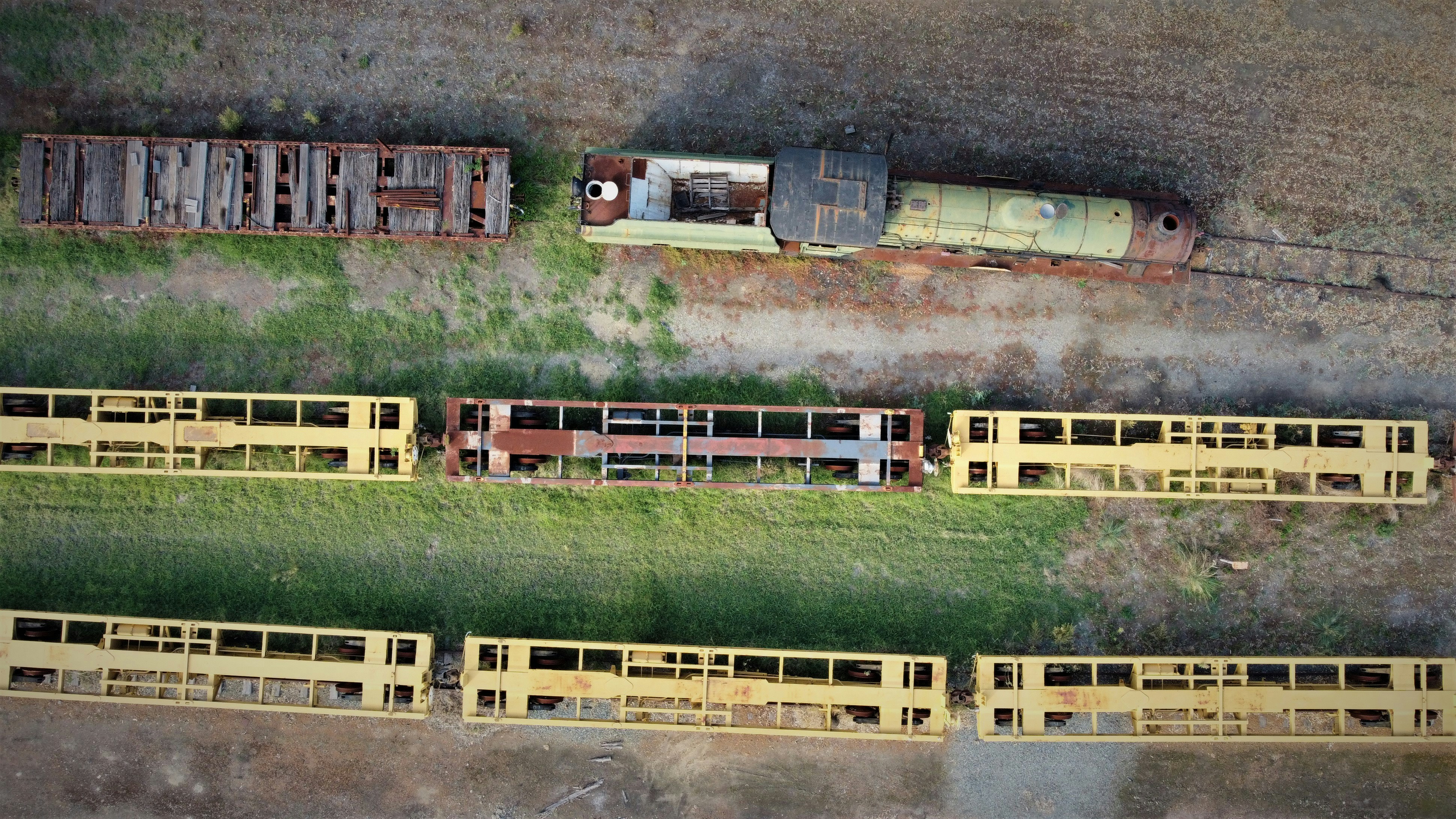 Overhead Yard: A Weathered Locomotive Framed by Sunlit Yellow Wagons