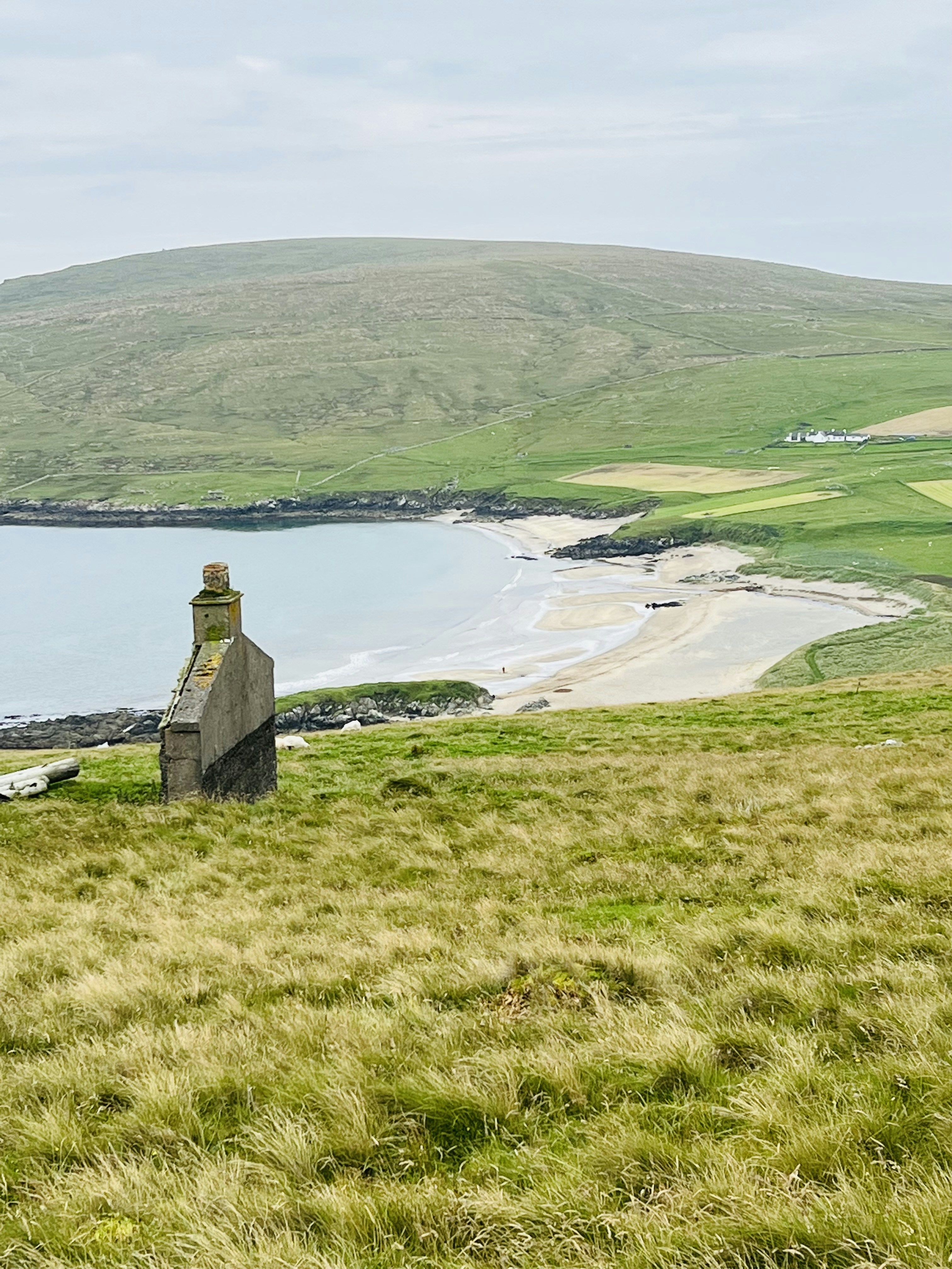 a stone tower on a grassy hill overlooking a body of water