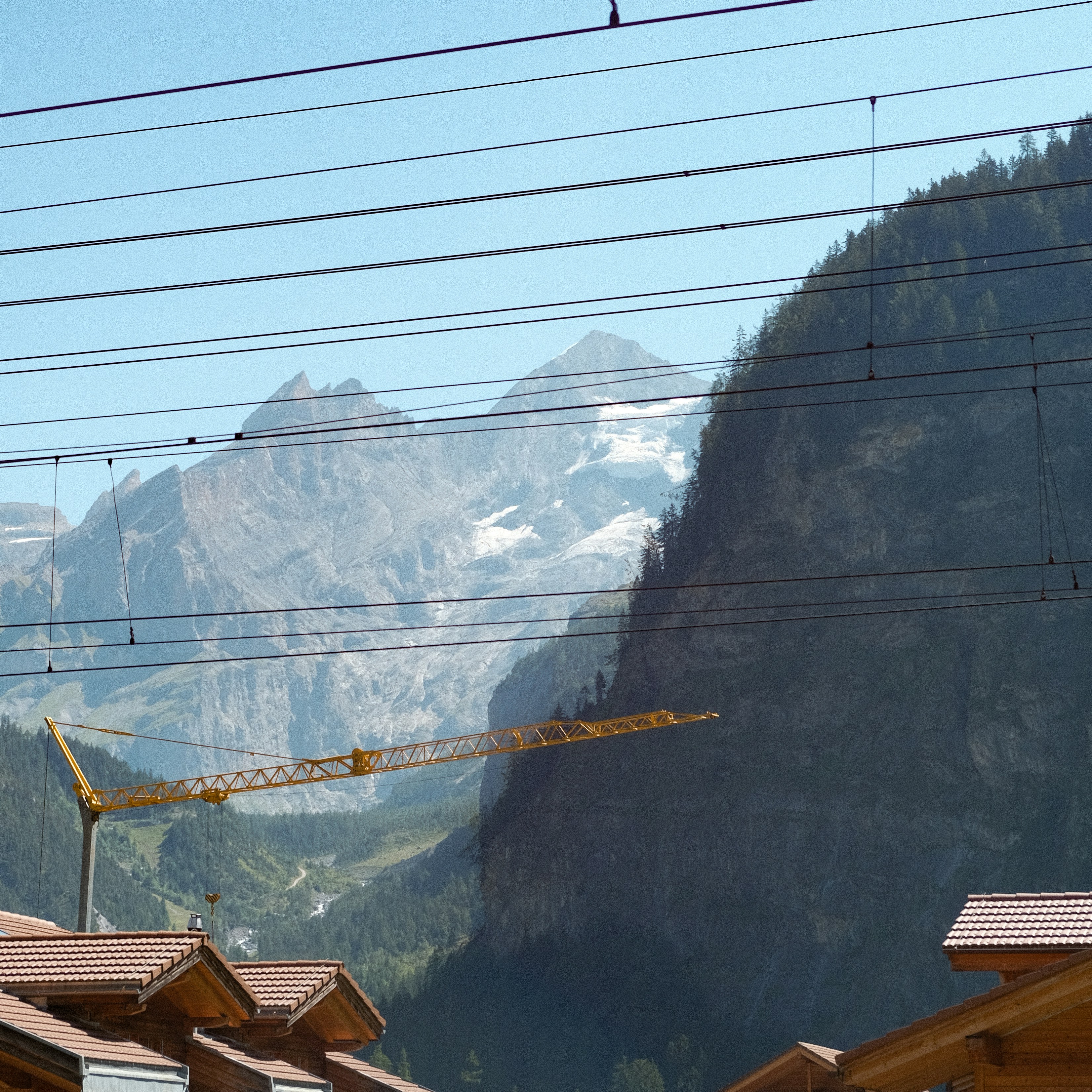 Yellow Crane Over Alpine Chalets Beneath a Web of Rails