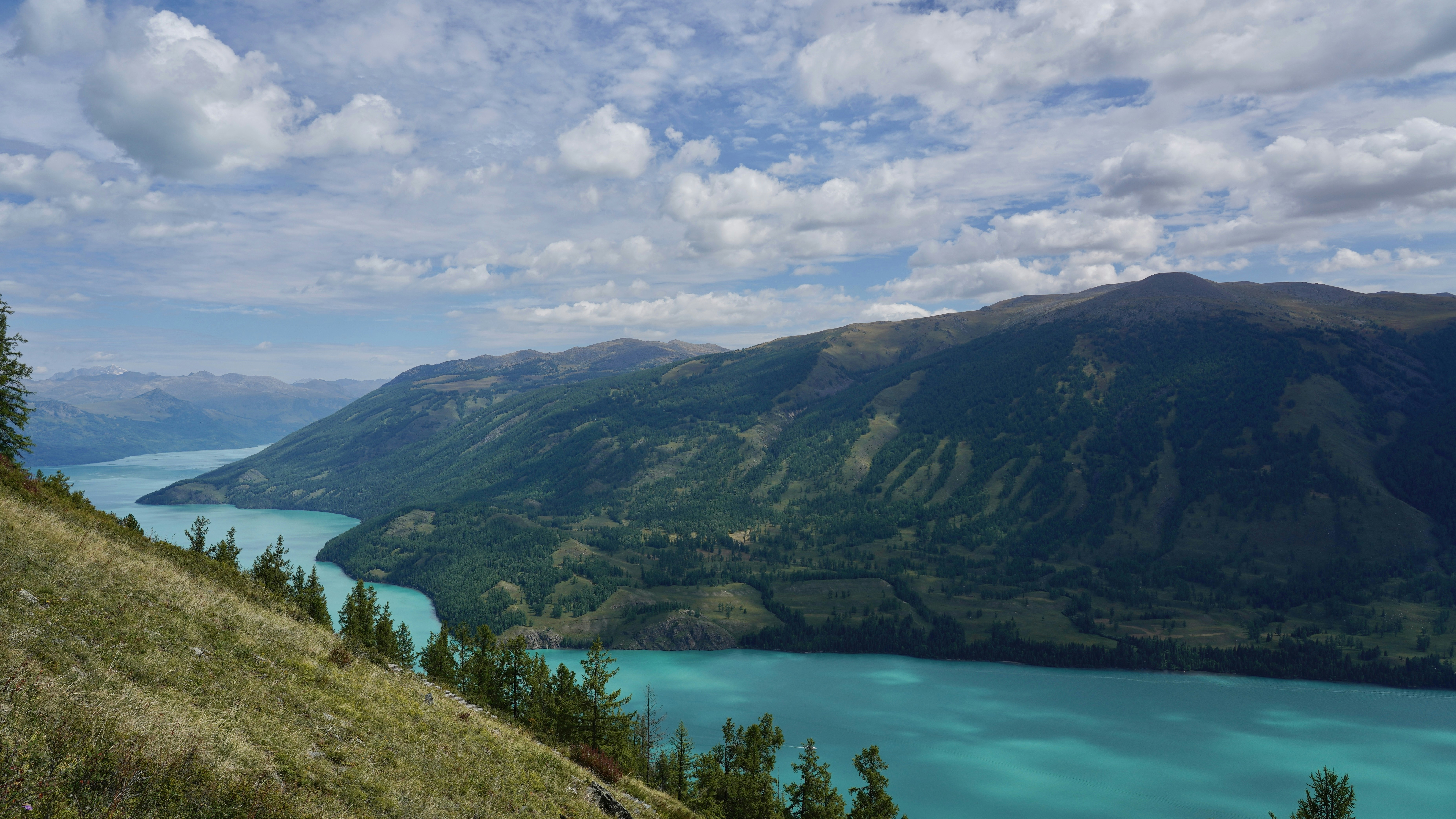 Vibrant turquoise lake framed by rugged mountains under a partly cloudy sky.