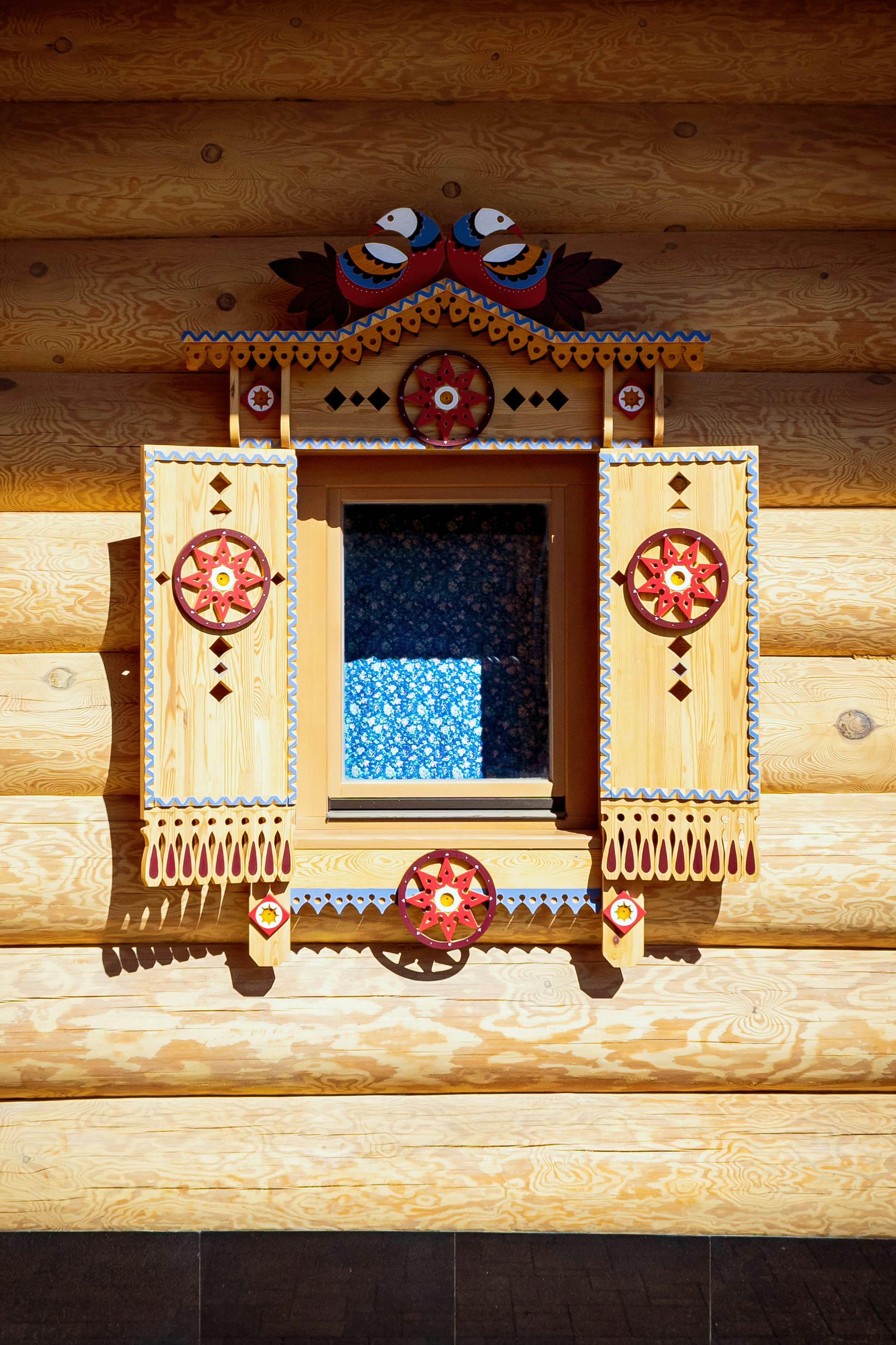 Colorfully decorated wooden window with intricate designs and floral patterns, showcasing traditional craftsmanship.