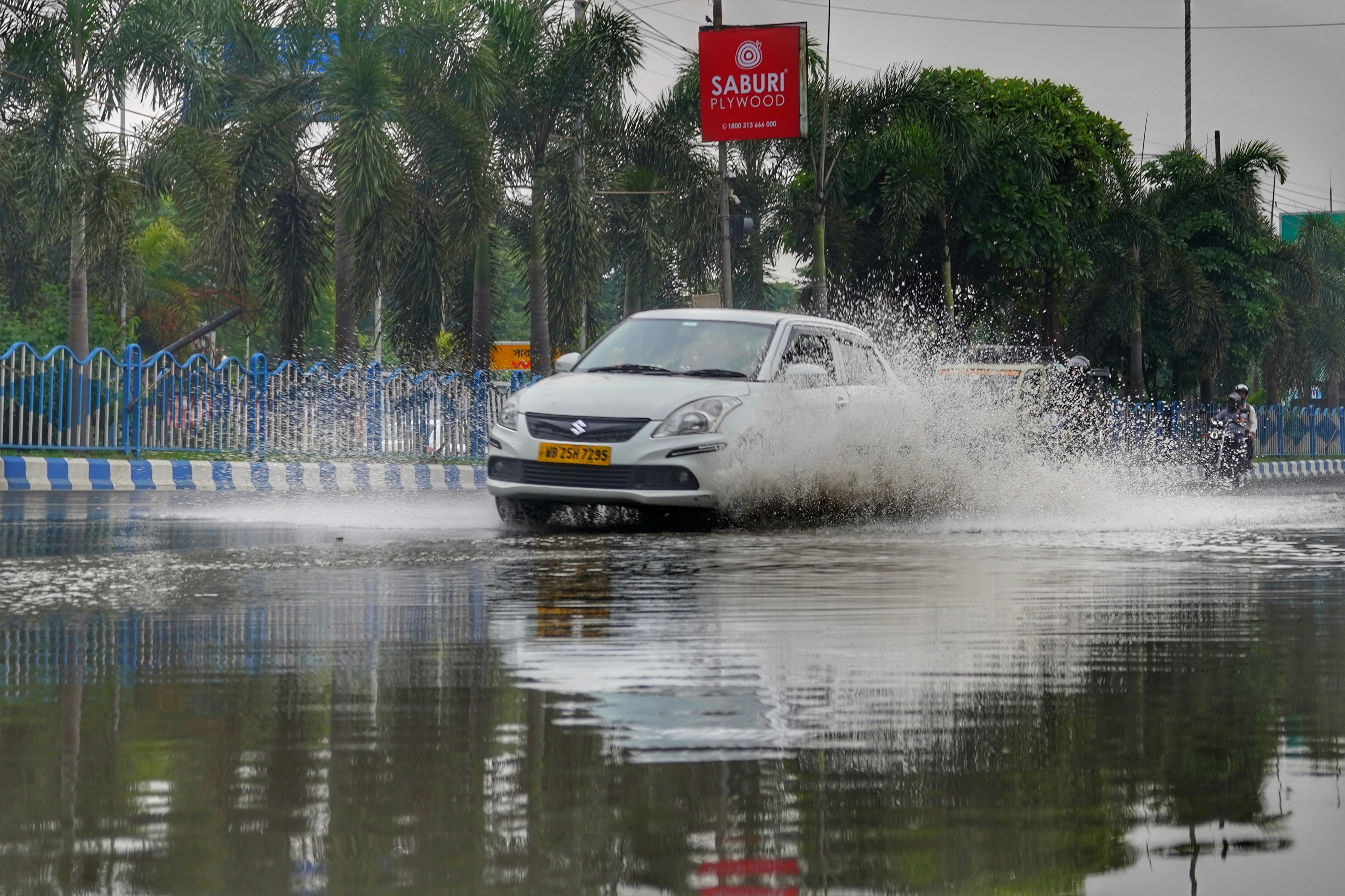 White Sedan Through Floodwater: A Charged Spray and Reflective Ripples