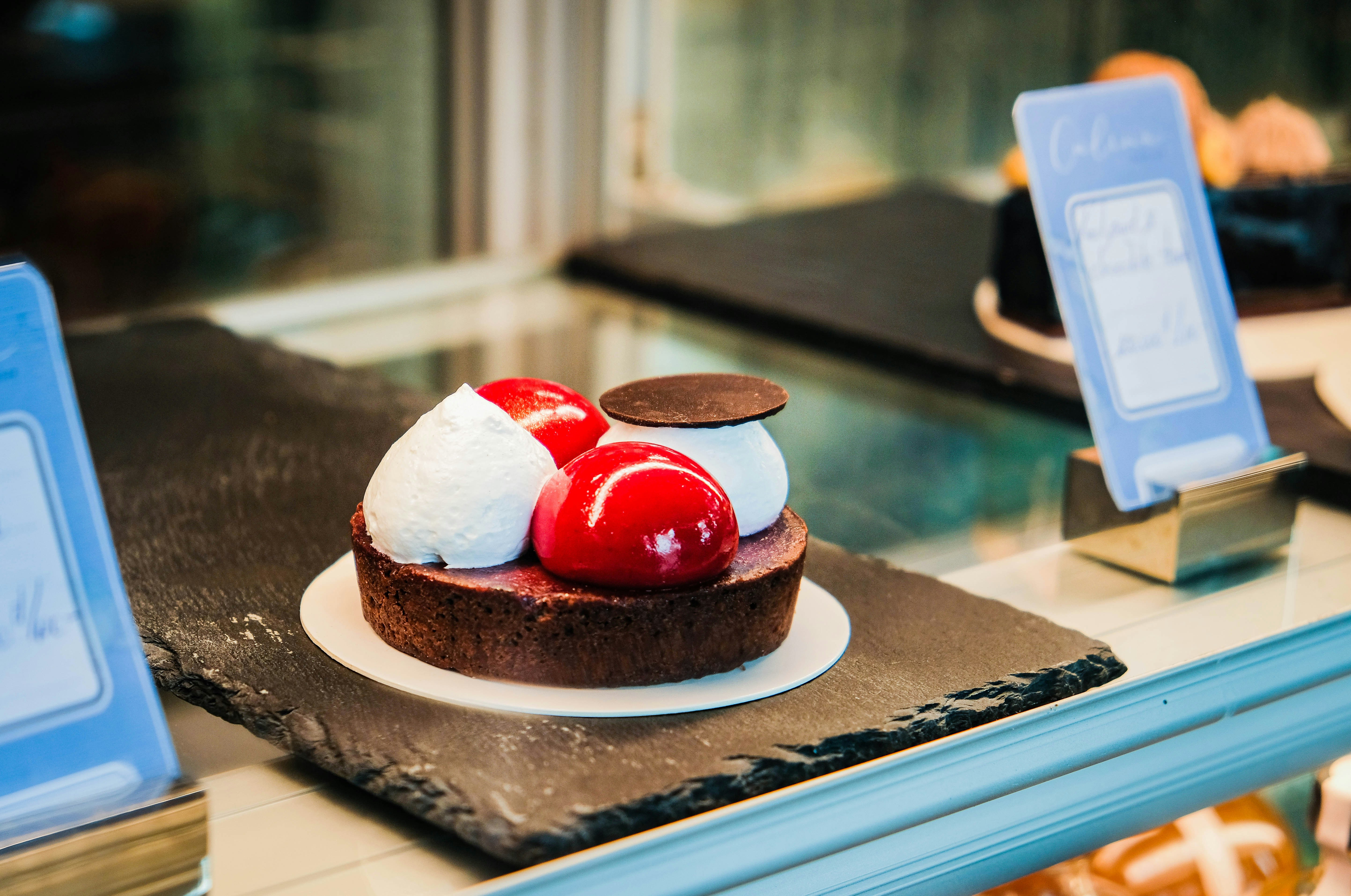 Chocolate tart with cherries and scoops on a slate platter in a bakery display