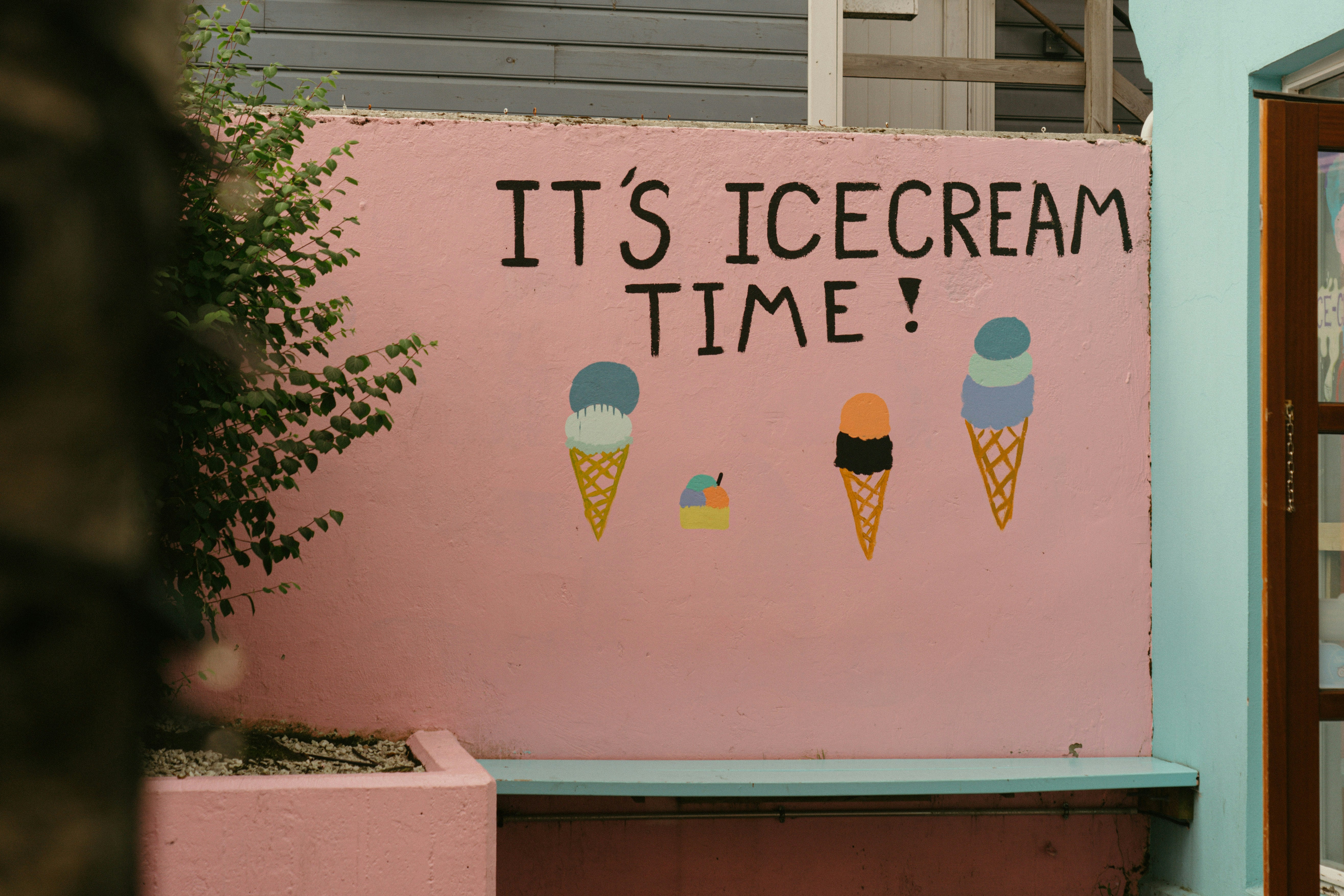 Colorful mural featuring ice cream cones and the phrase 'IT'S ICECREAM TIME!' on a pink wall, inviting passersby to indulge. 