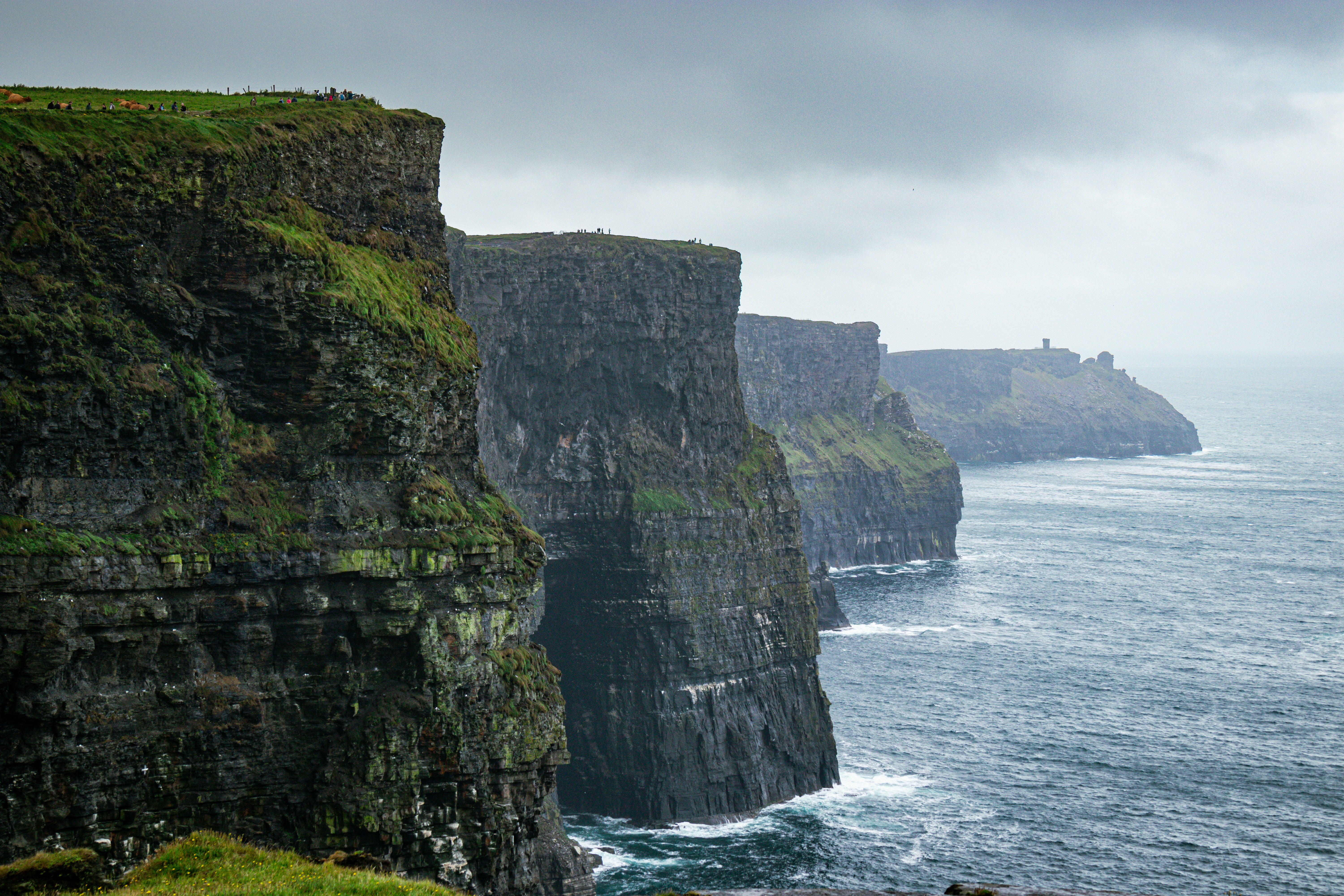 A cliff side with a body of water below with Cliffs of Moher in the ...