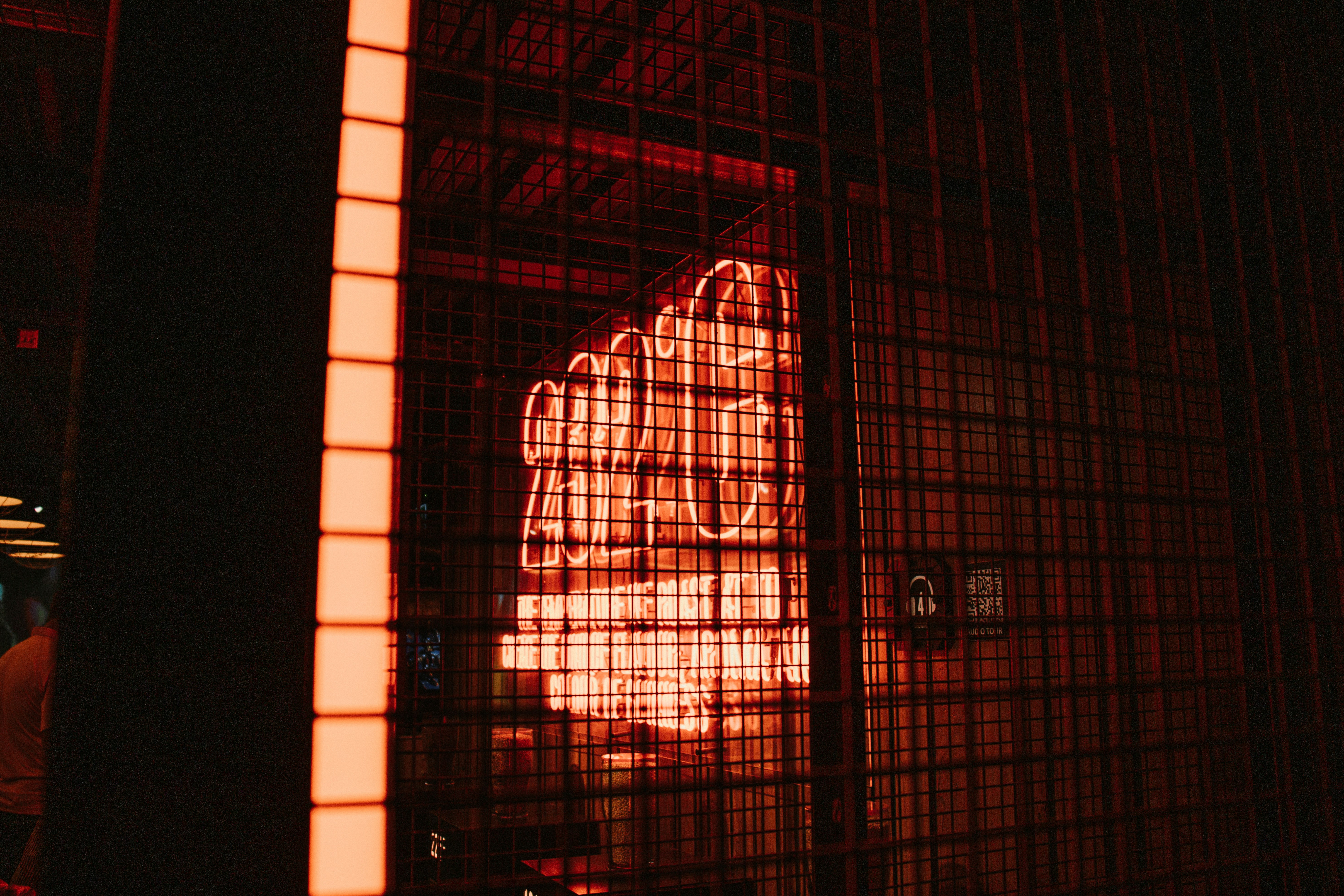 Crimson Neon Through a Metal Grid