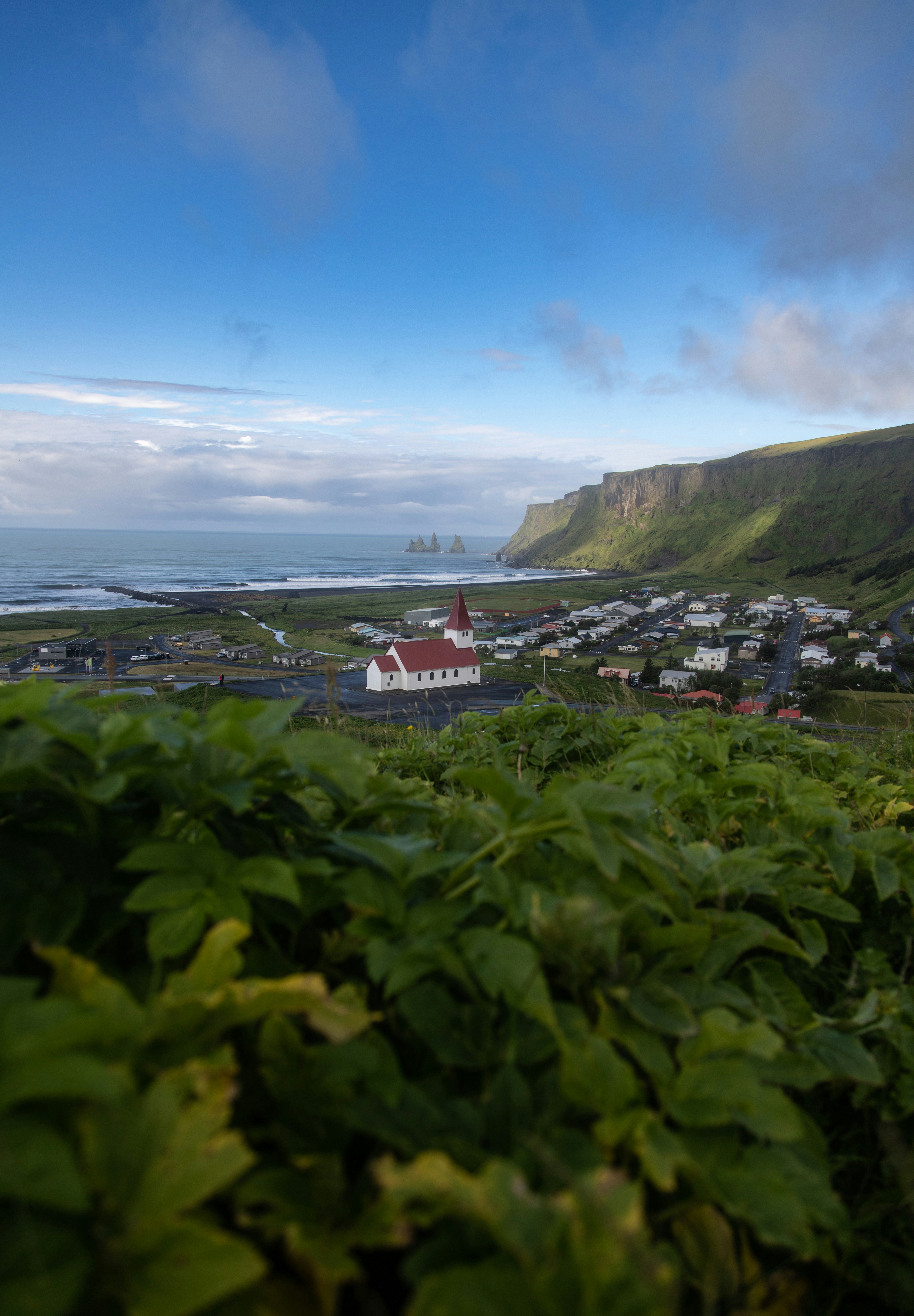 Red-roofed church anchors a cliffside village beneath expansive coastal skies