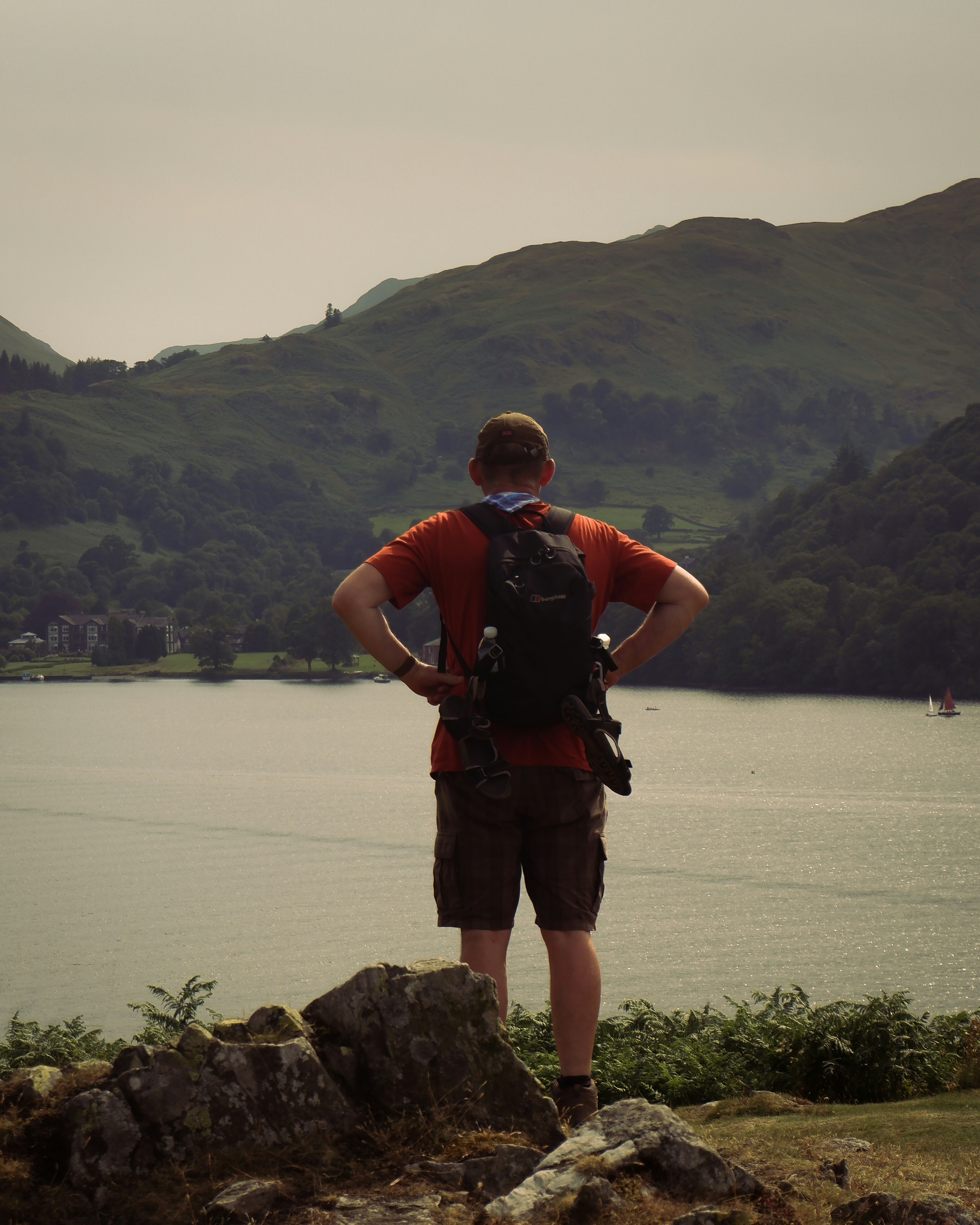 Red-Clad Hiker Scanning a Misty Lake from a Rocky Promontory