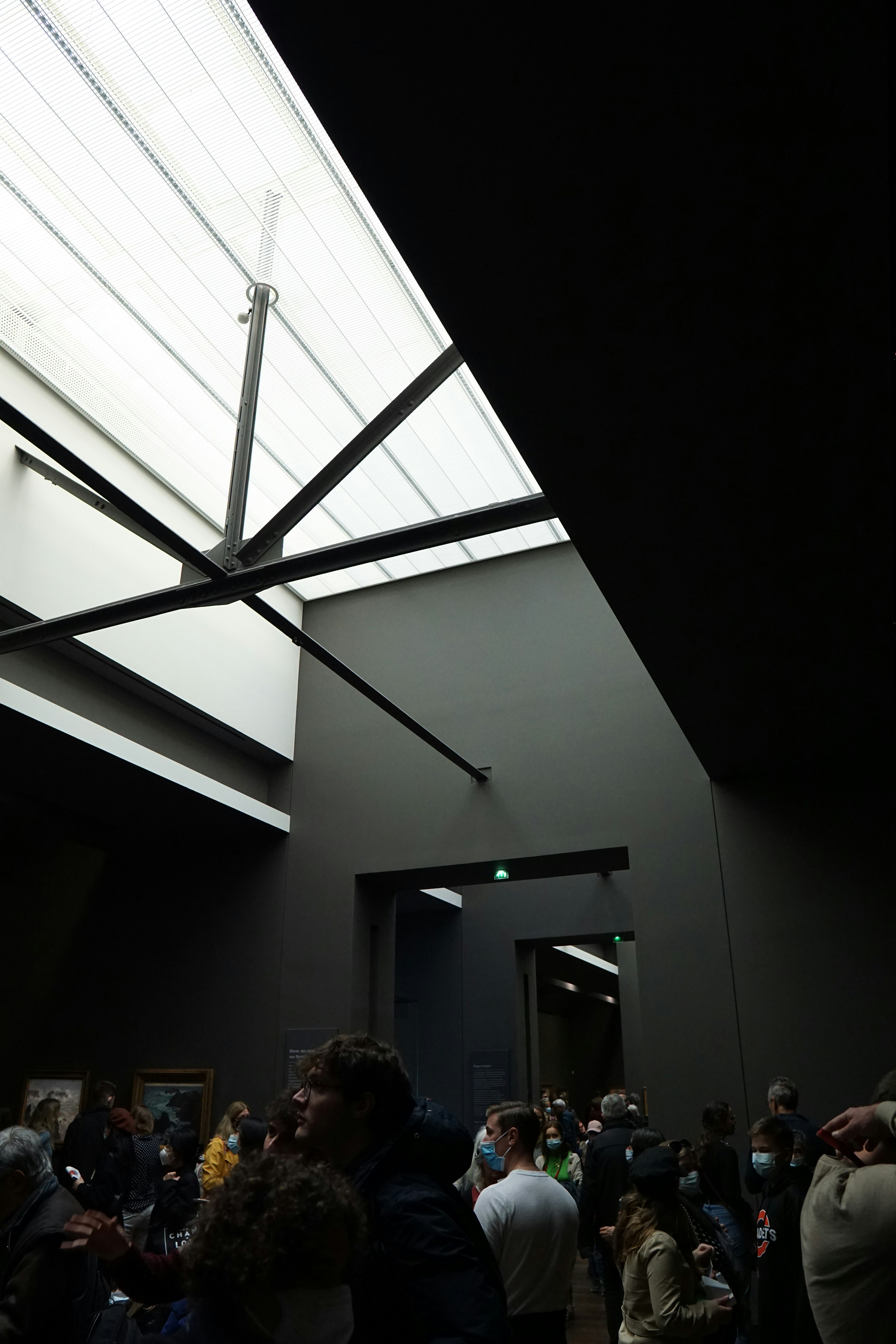 A Quiet Corridor of People Under A Glowing Atrium Roof