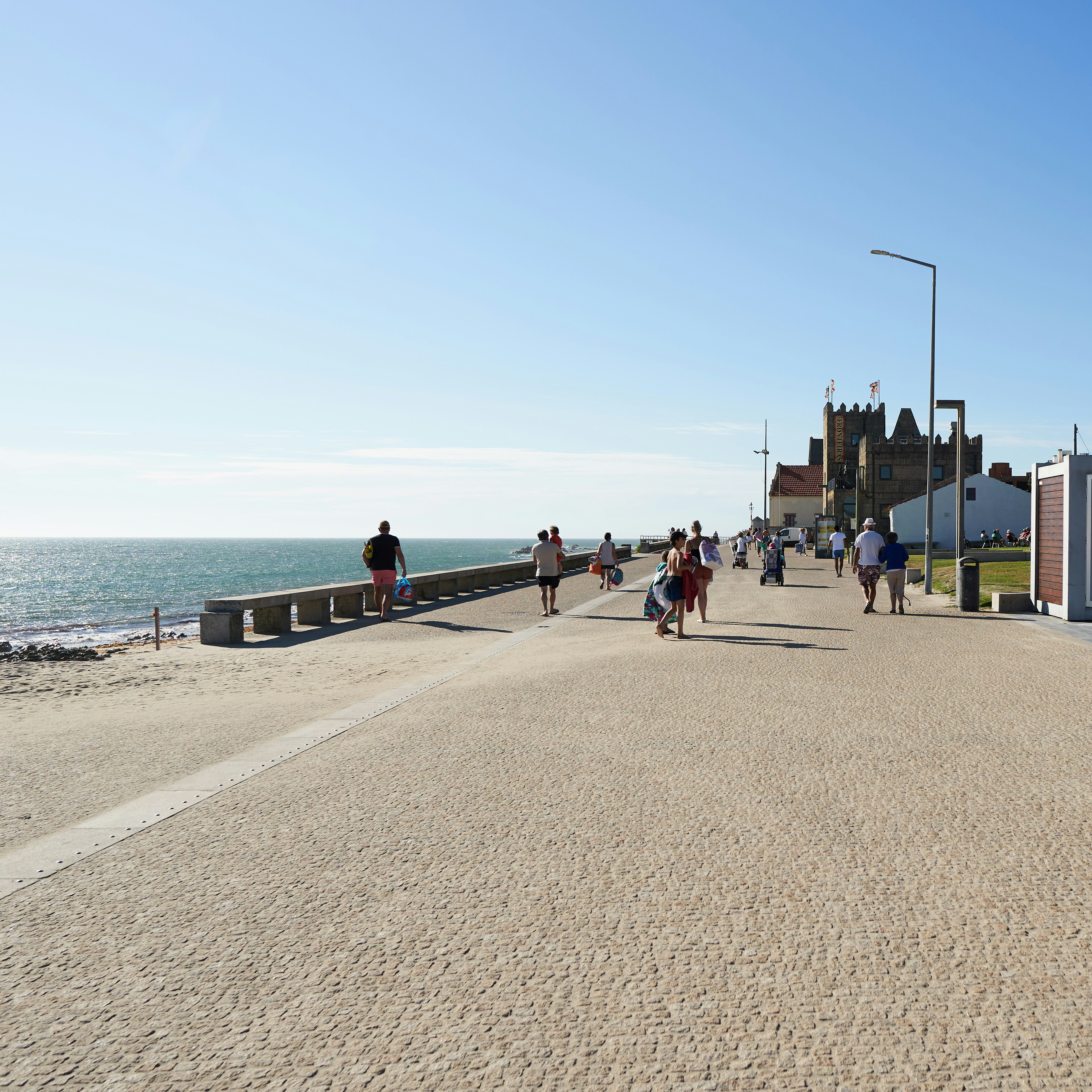 Seaside Promenade Toward a Castle-Faced Fortress Under a Clear Sky
