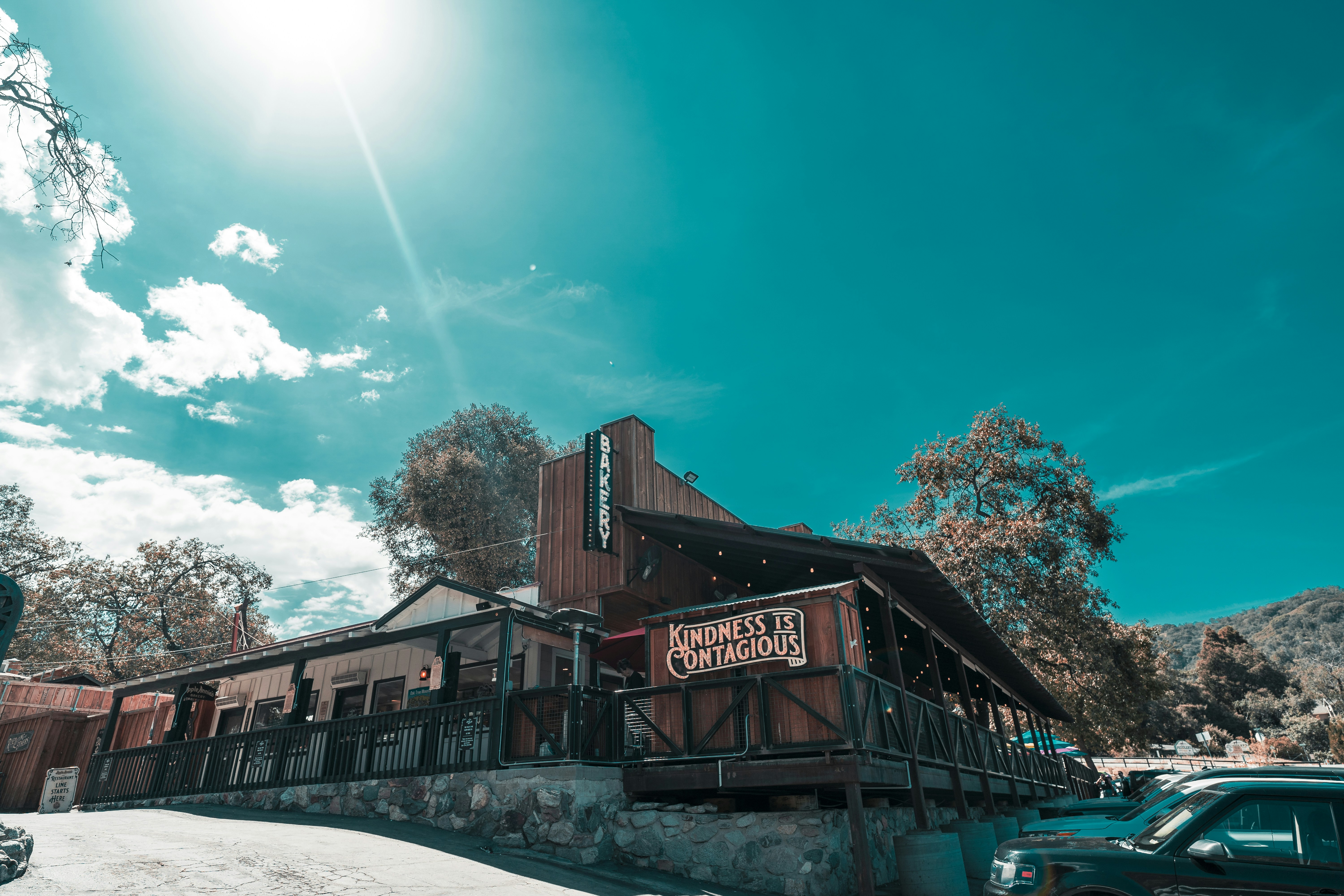 Kindness on the Deck: A Rustic Hillside Eatery Under a Teal Sky