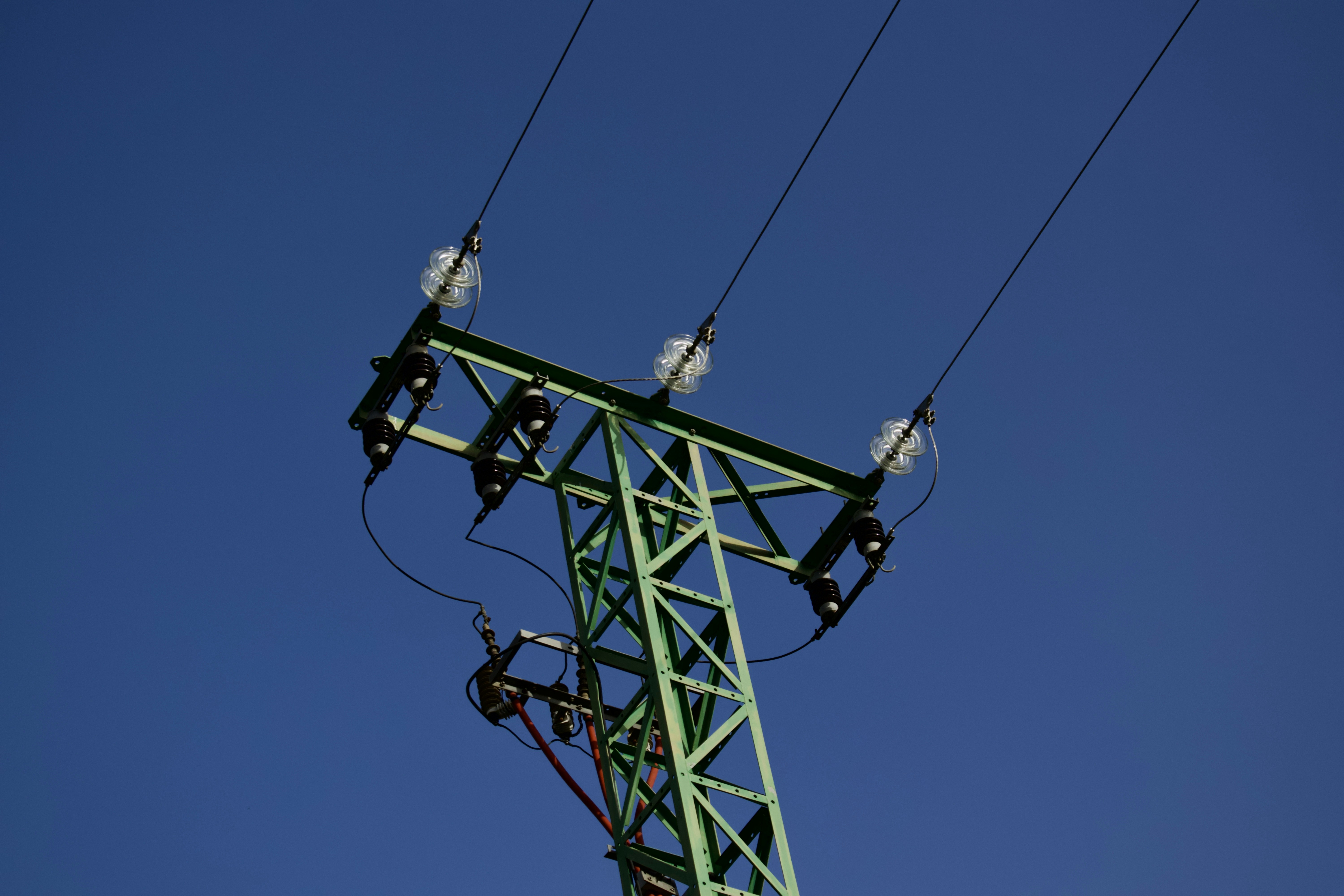 Transmission tower with power lines against a clear blue sky.