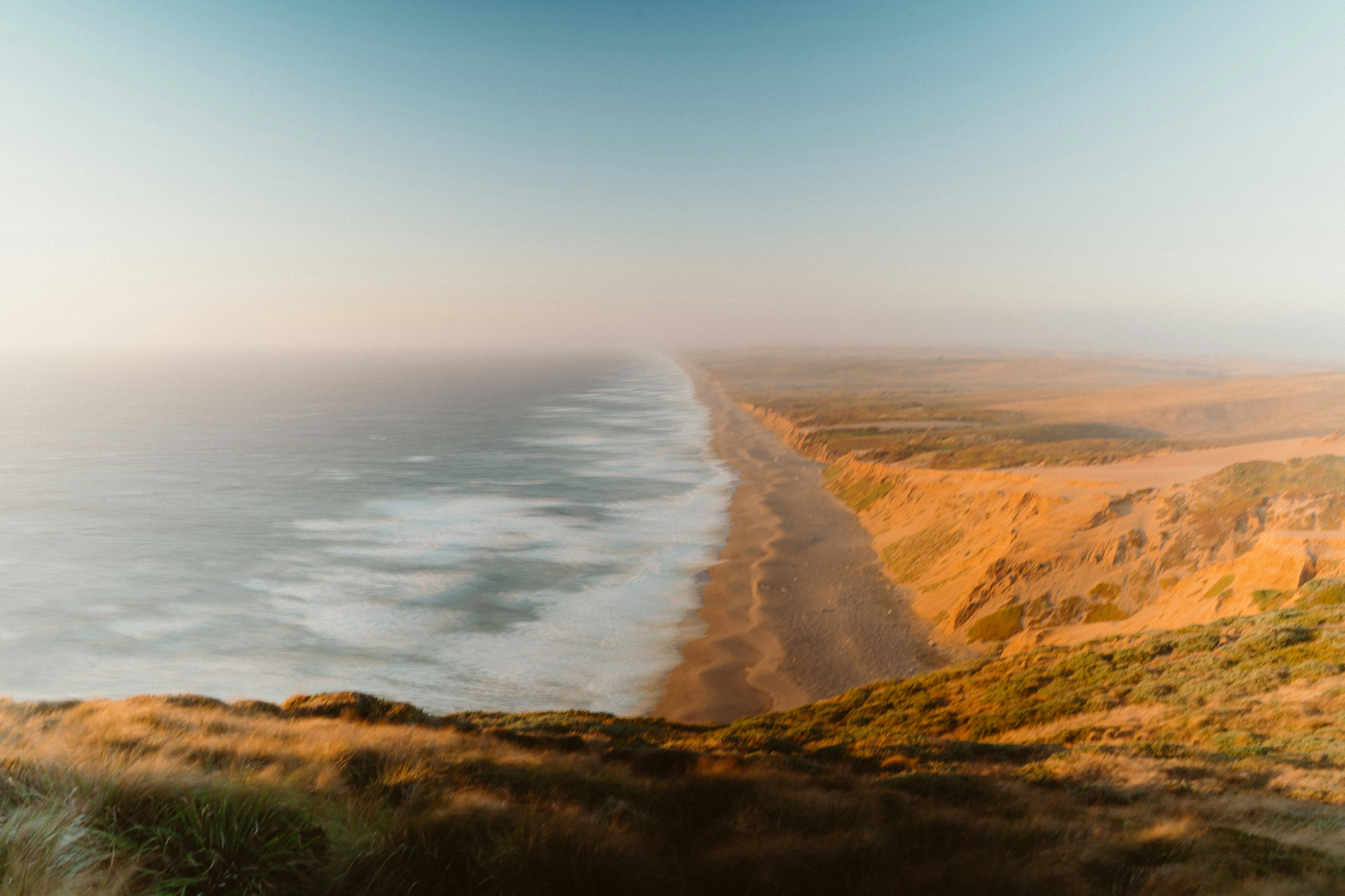 Una playa de arena con un cuerpo de agua en el fondo foto – Imagen de ...