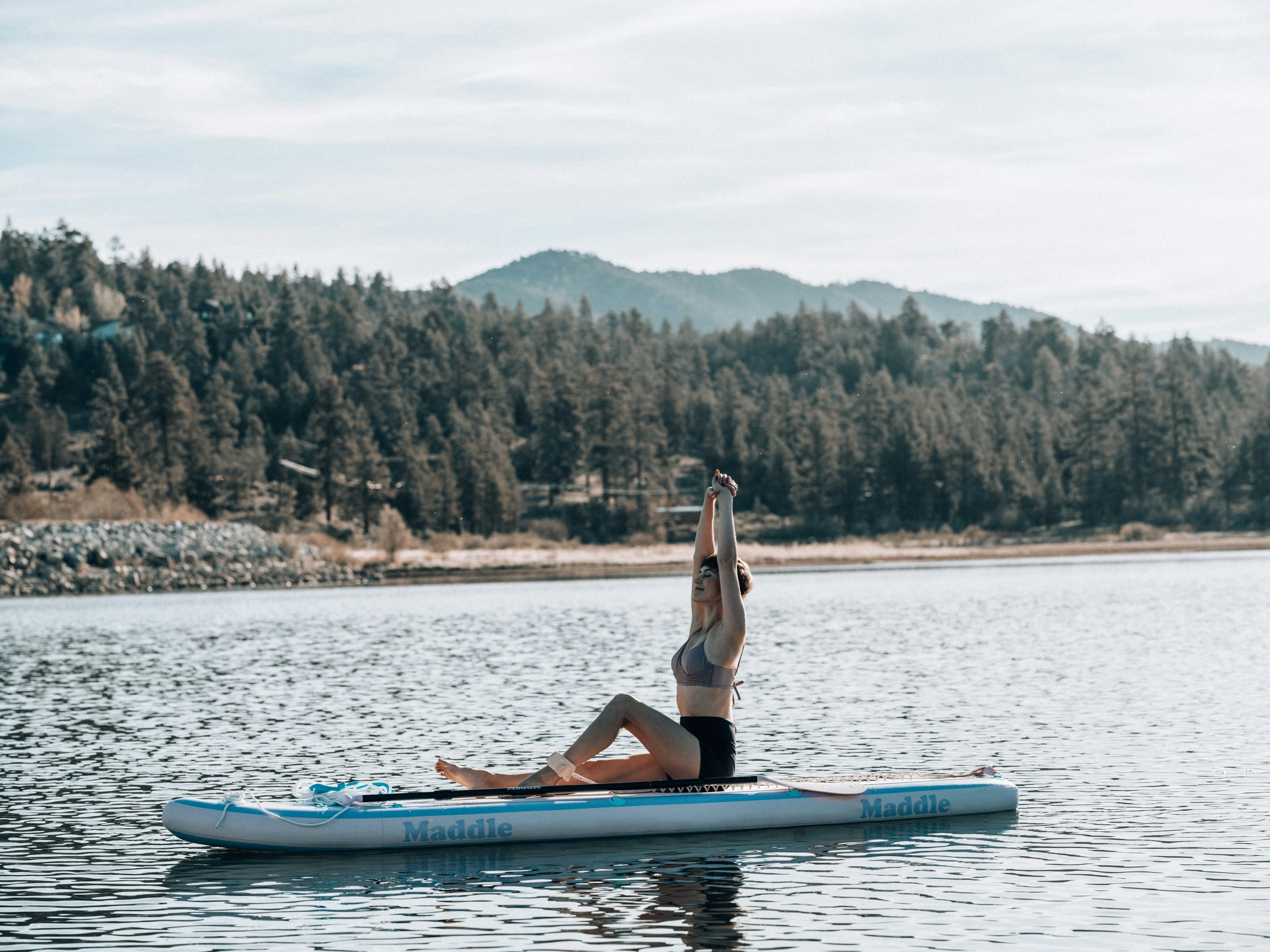 A person doing a handstand on a paddle board in a lake photo – Free ...
