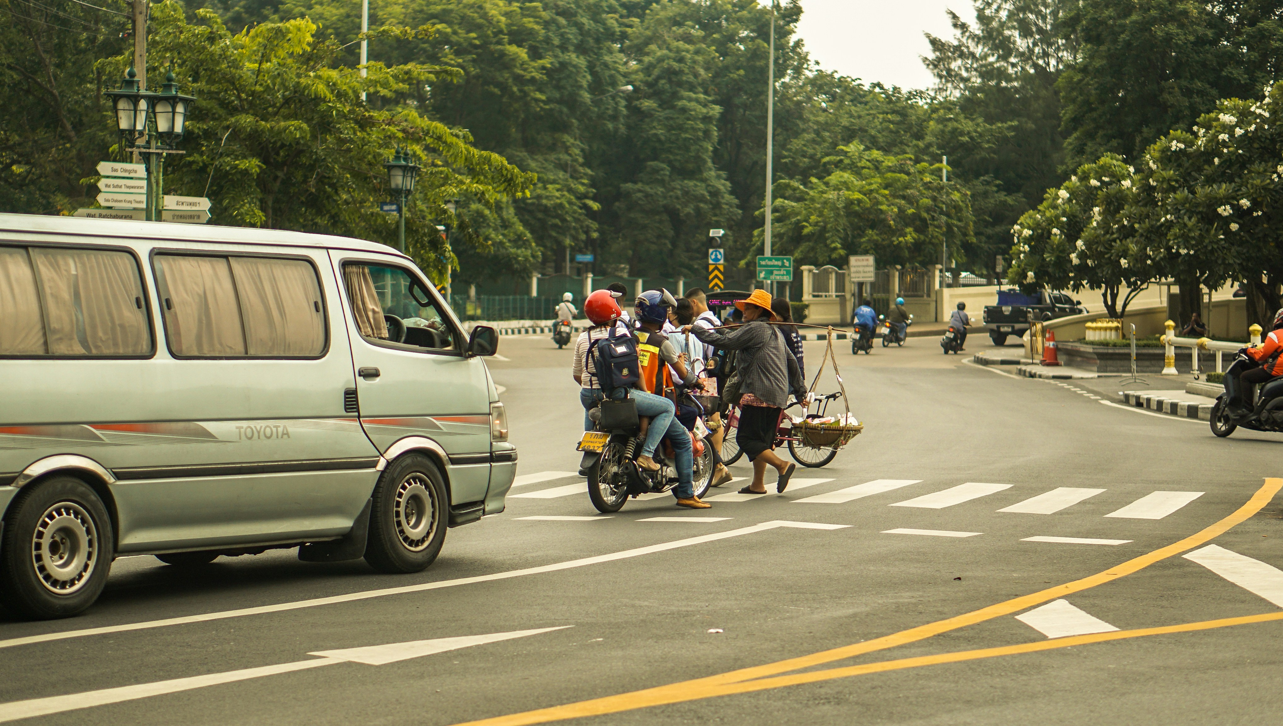 A group of people ride on a motorcycle down a street photo – Free ...
