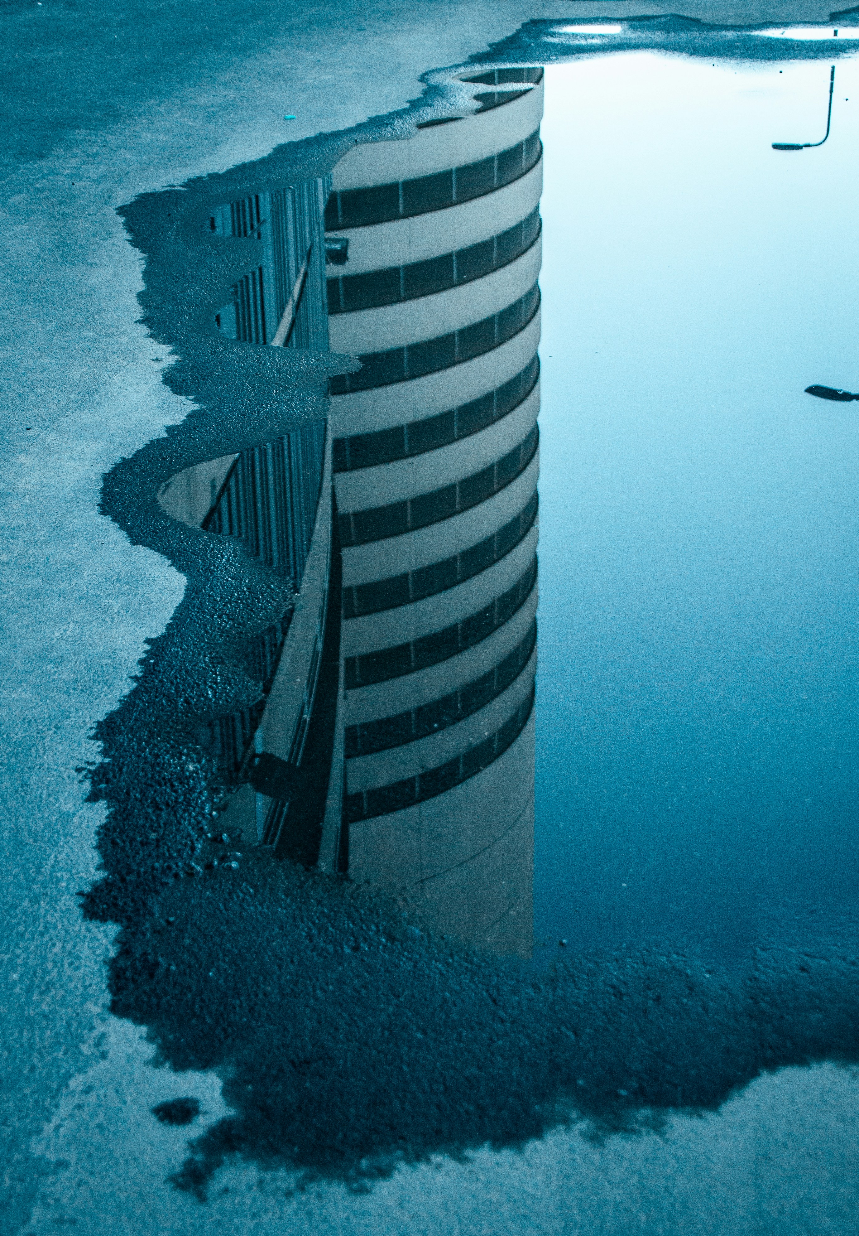 Blue Mirror: Reflection of a Circular Tower in a Fractured Puddle