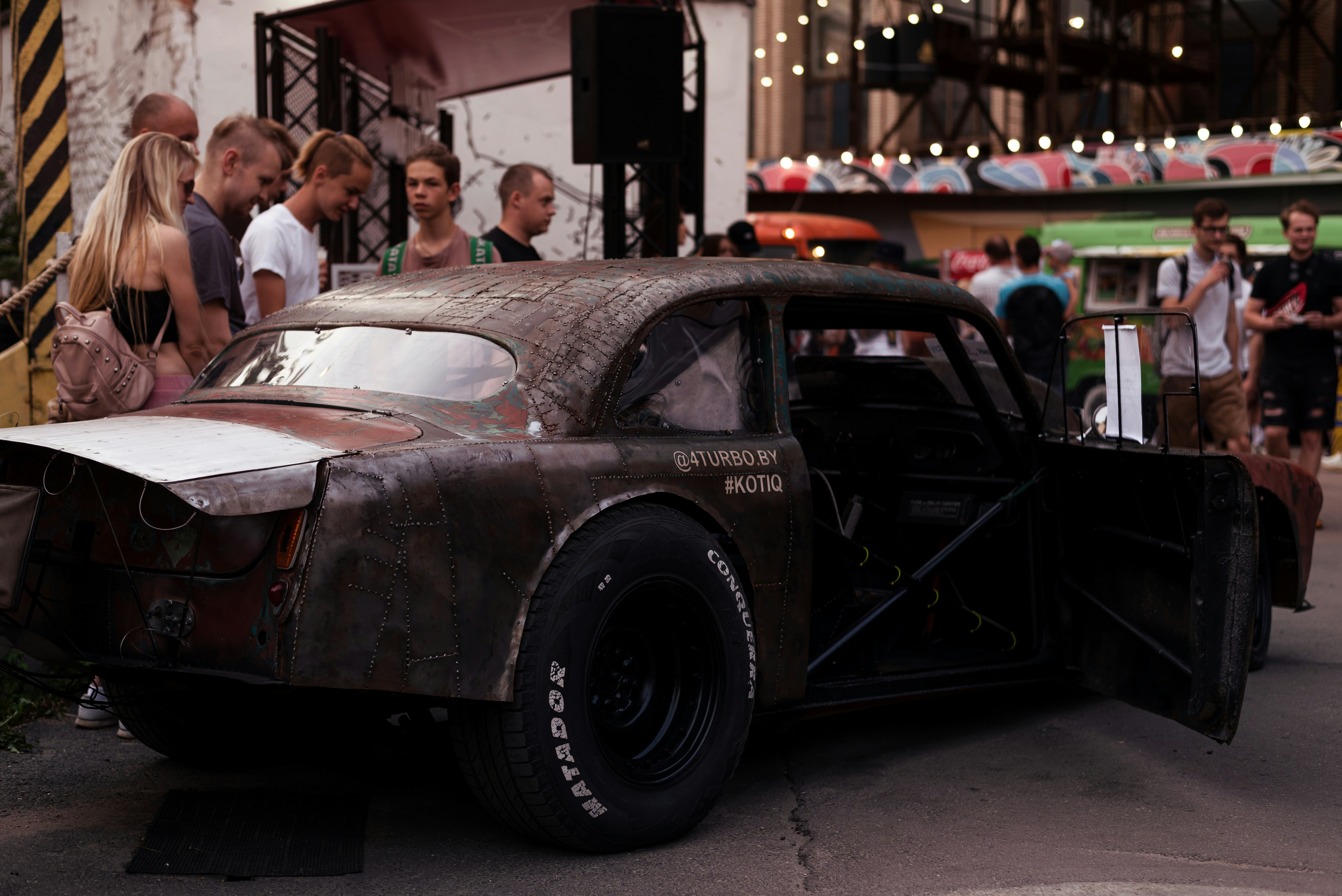 Patina at the Pulse: A rusted 1950s cruiser anchors a street-fair moment