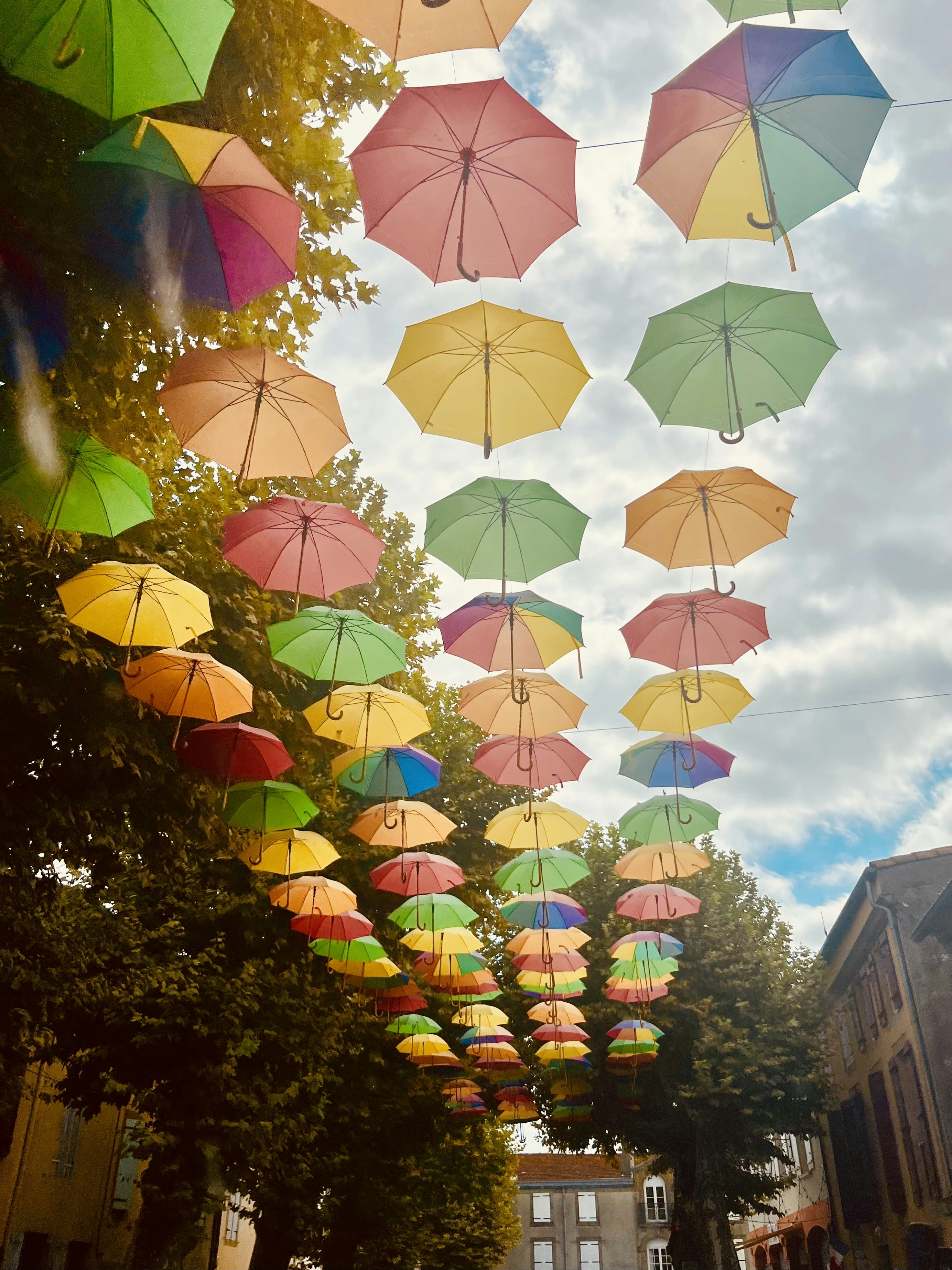 Chromatic Canopy: A Rainbow of Umbrellas Over a Sunlit Street