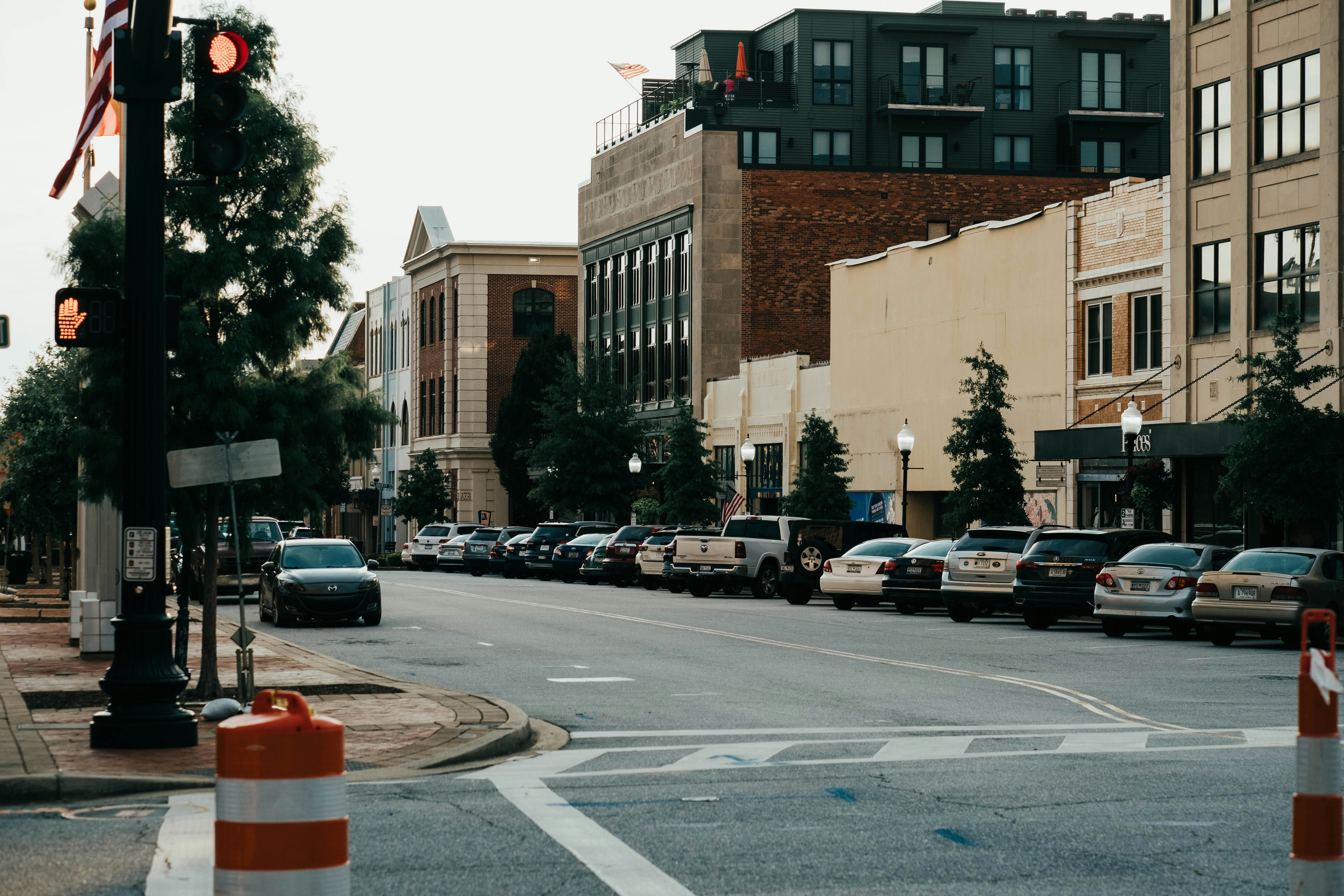A serene view of a city street lined with parked cars and quaint buildings, showcasing a blend of urban life and calmness.