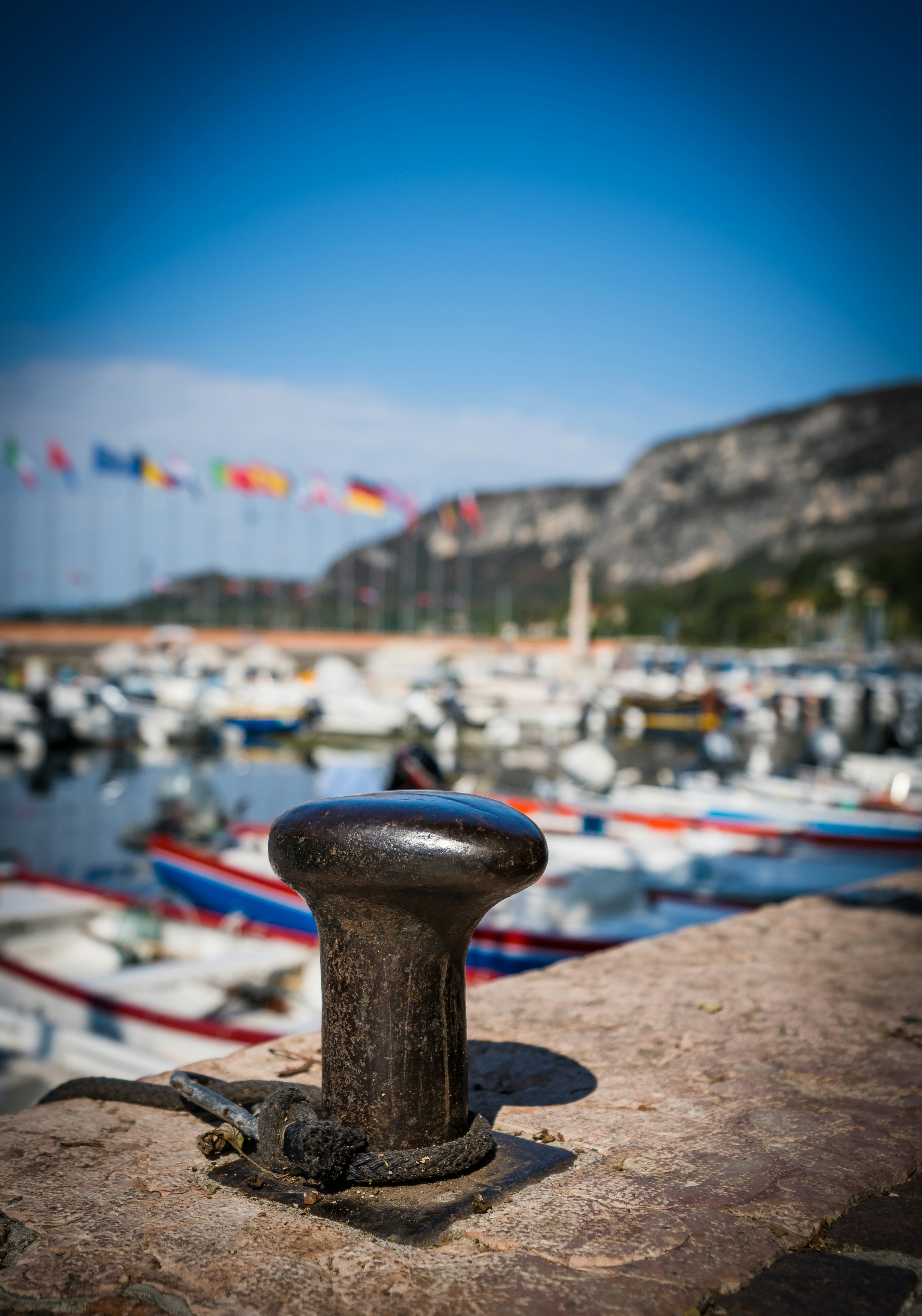 Anchored in Detail: A Weathered Bollard Framing a Quiet Marina Blur