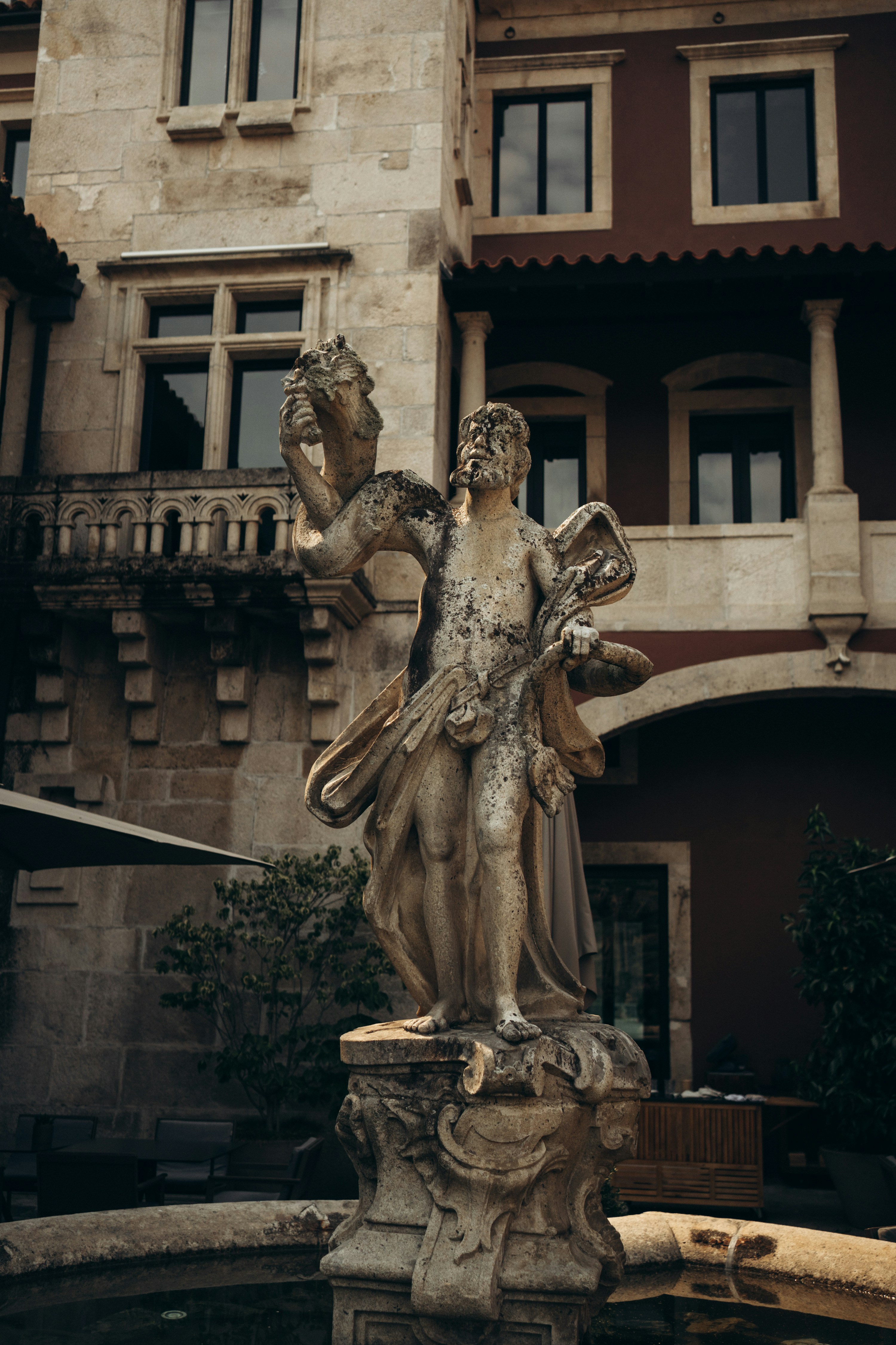 Solitude in Stone: A Weathered Statue Framed by a Historic European Courtyard