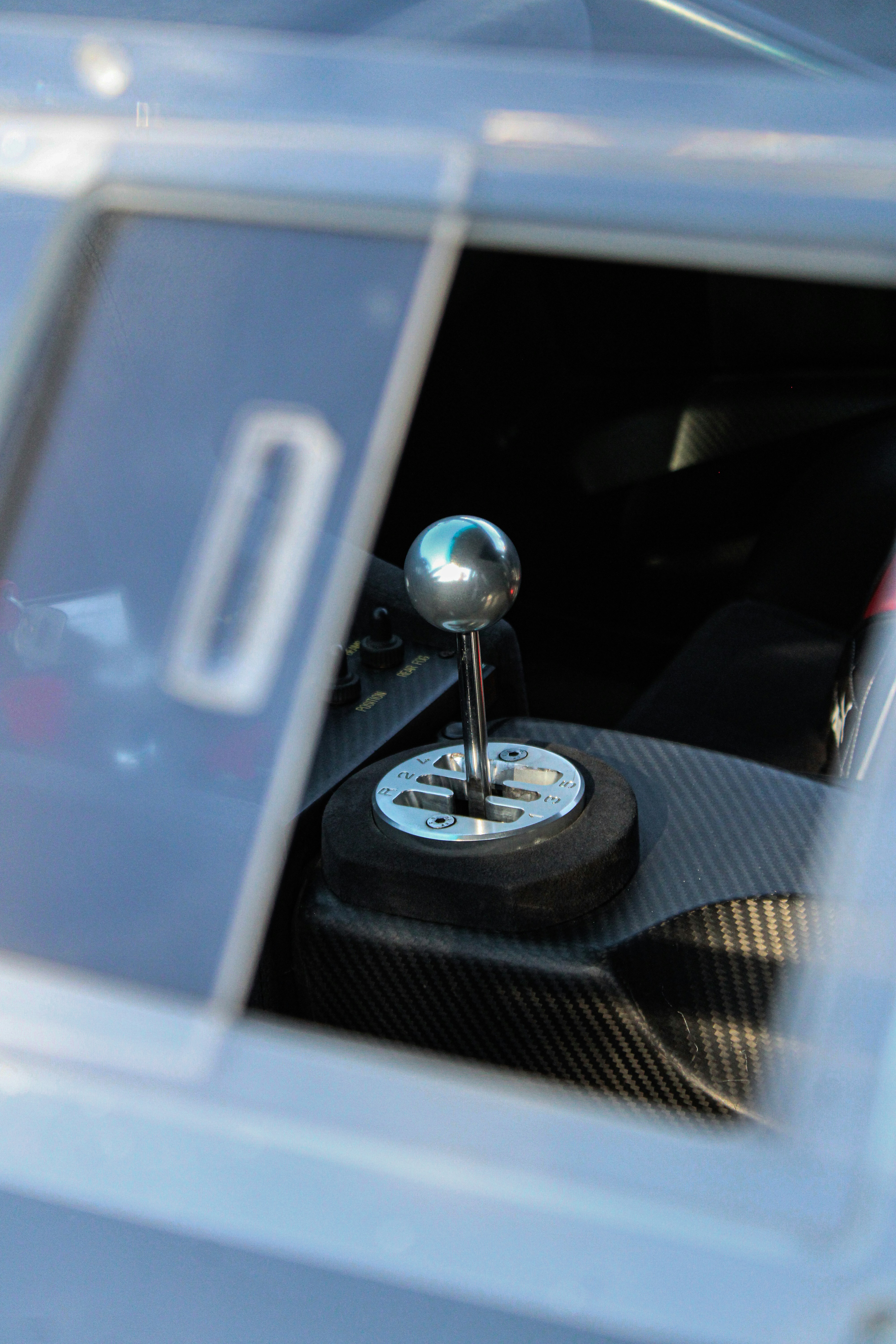 Chrome Ball Joystick Rising from a Carbon-Fiber Cockpit