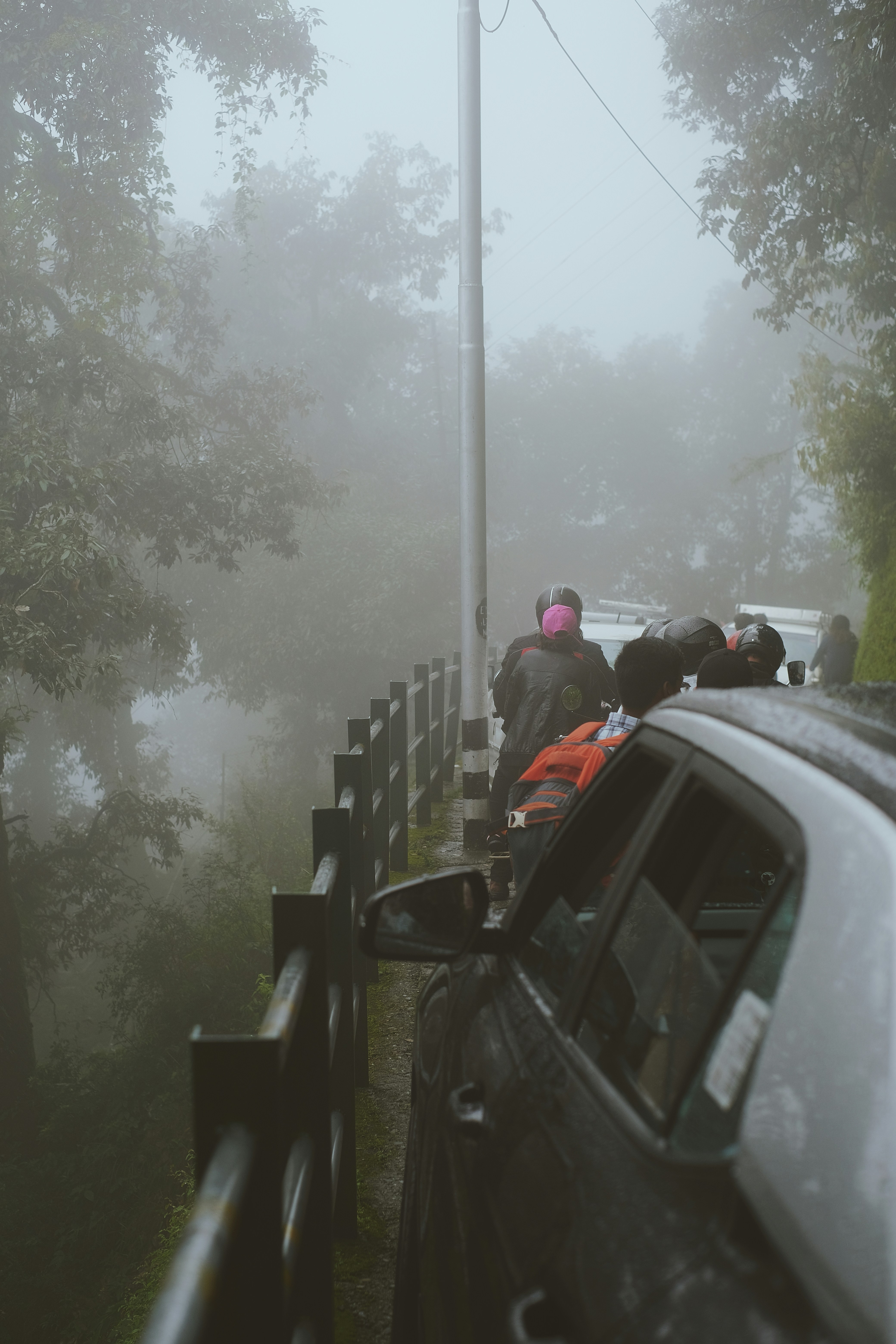Fogged overlook: hikers queued along a misty cliffside road
