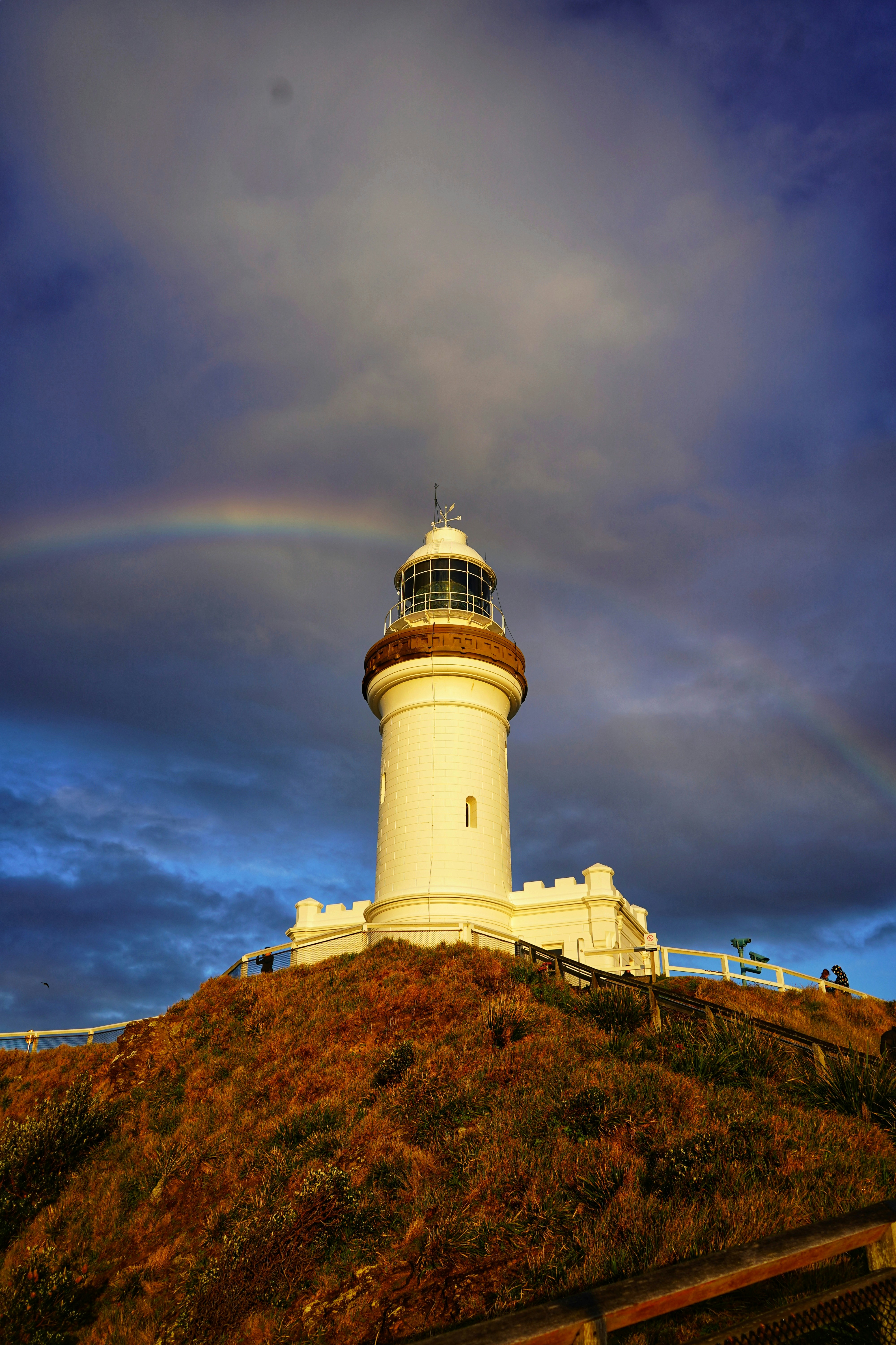 Rainbow Arch Over a Cliffside Lighthouse at Golden Hour