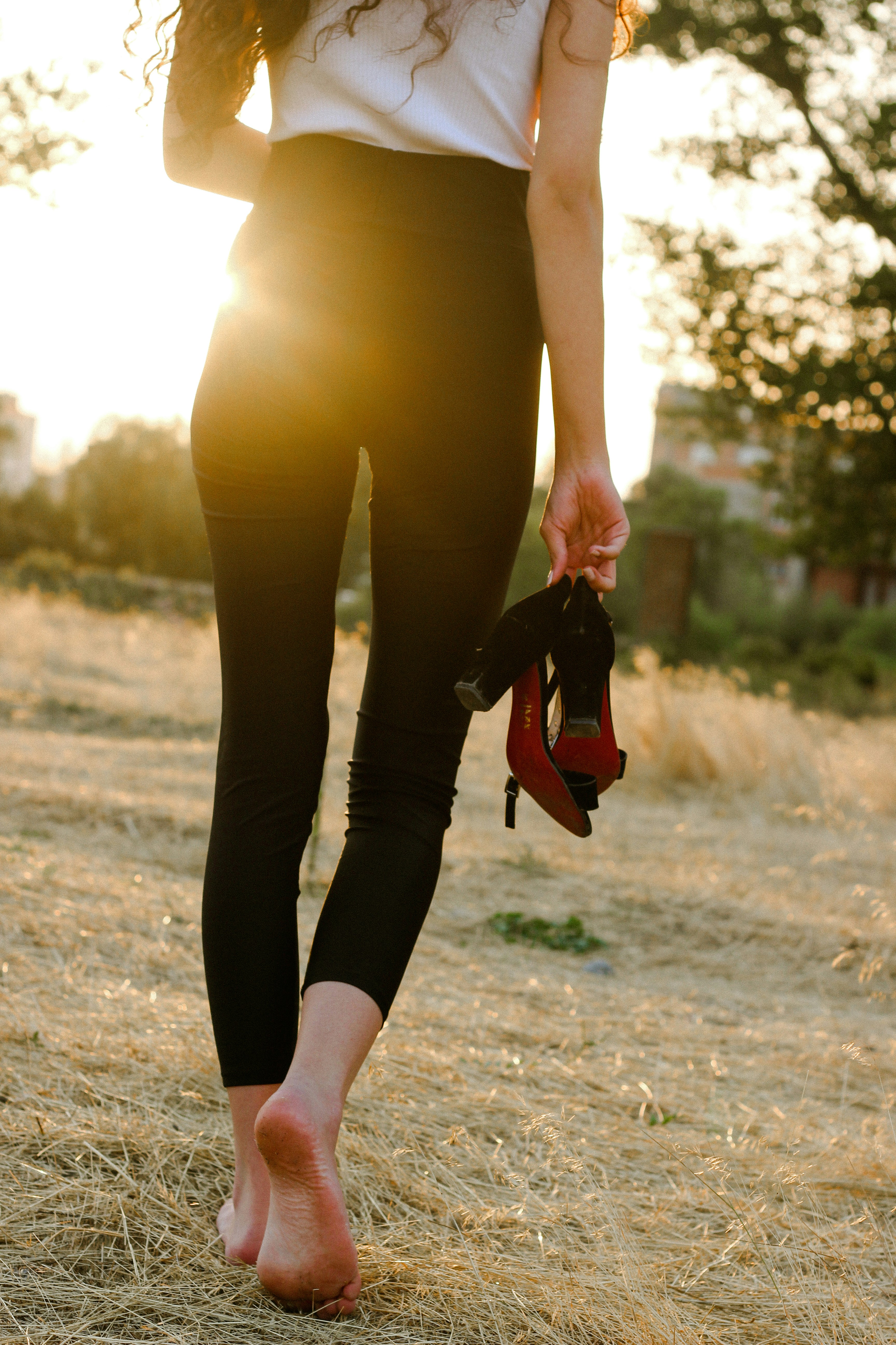Sunlit stride: a barefoot ascent with heels in hand