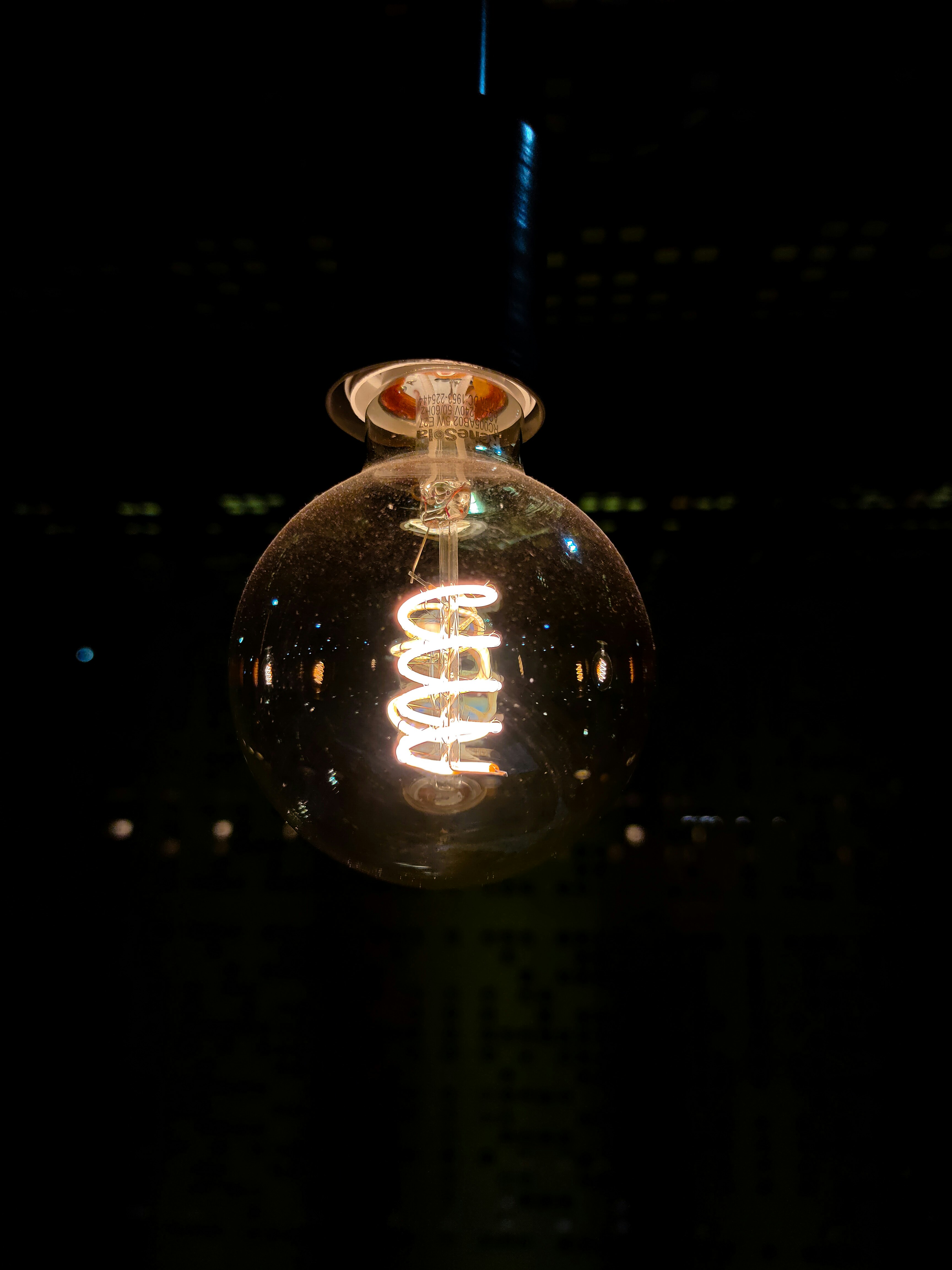 Spiral Glow: A Lone Filament in a Dark Glass Globe