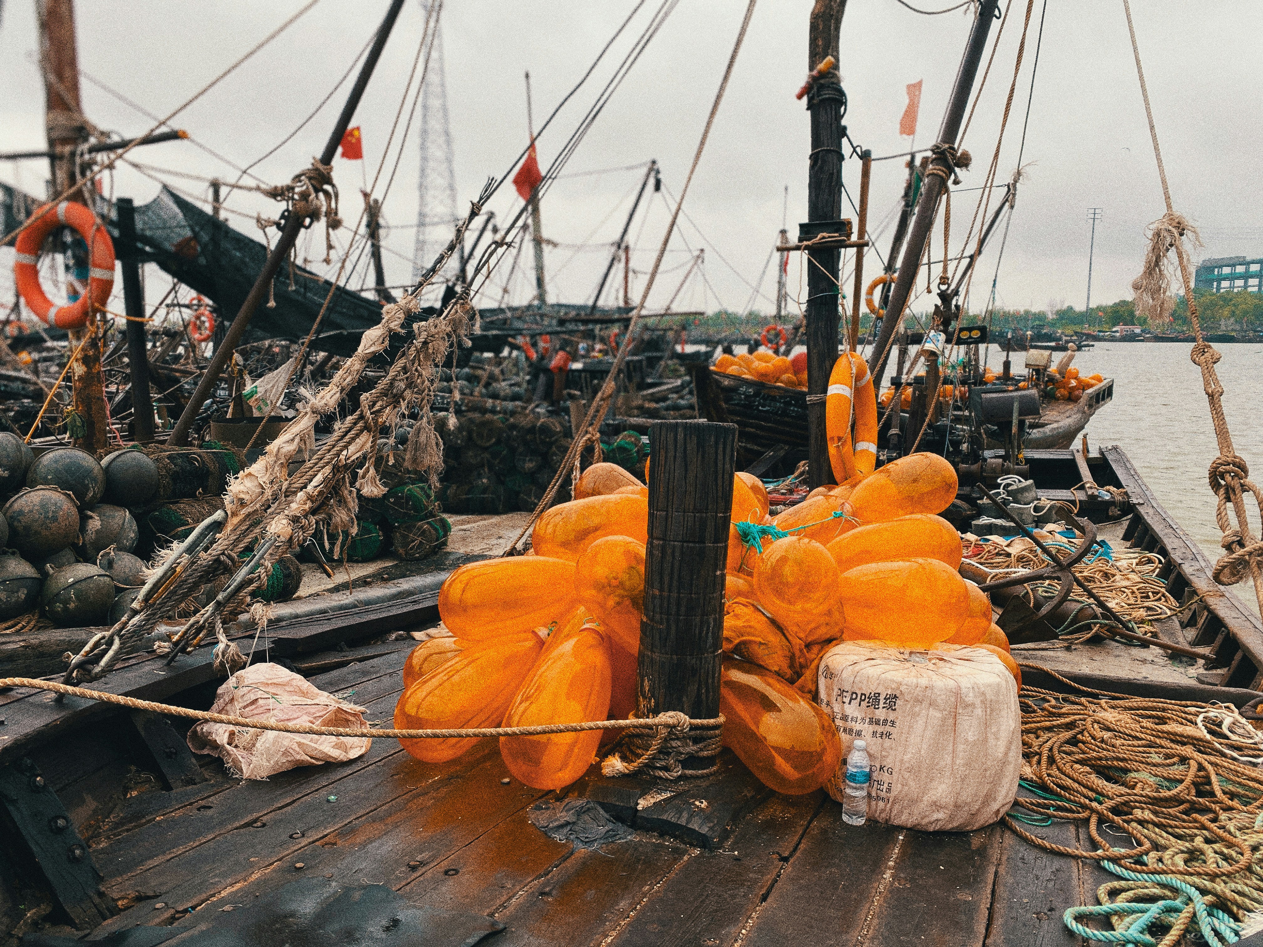 Orange Buoy Stack on a Weathered Dock Amid Fishing Gear