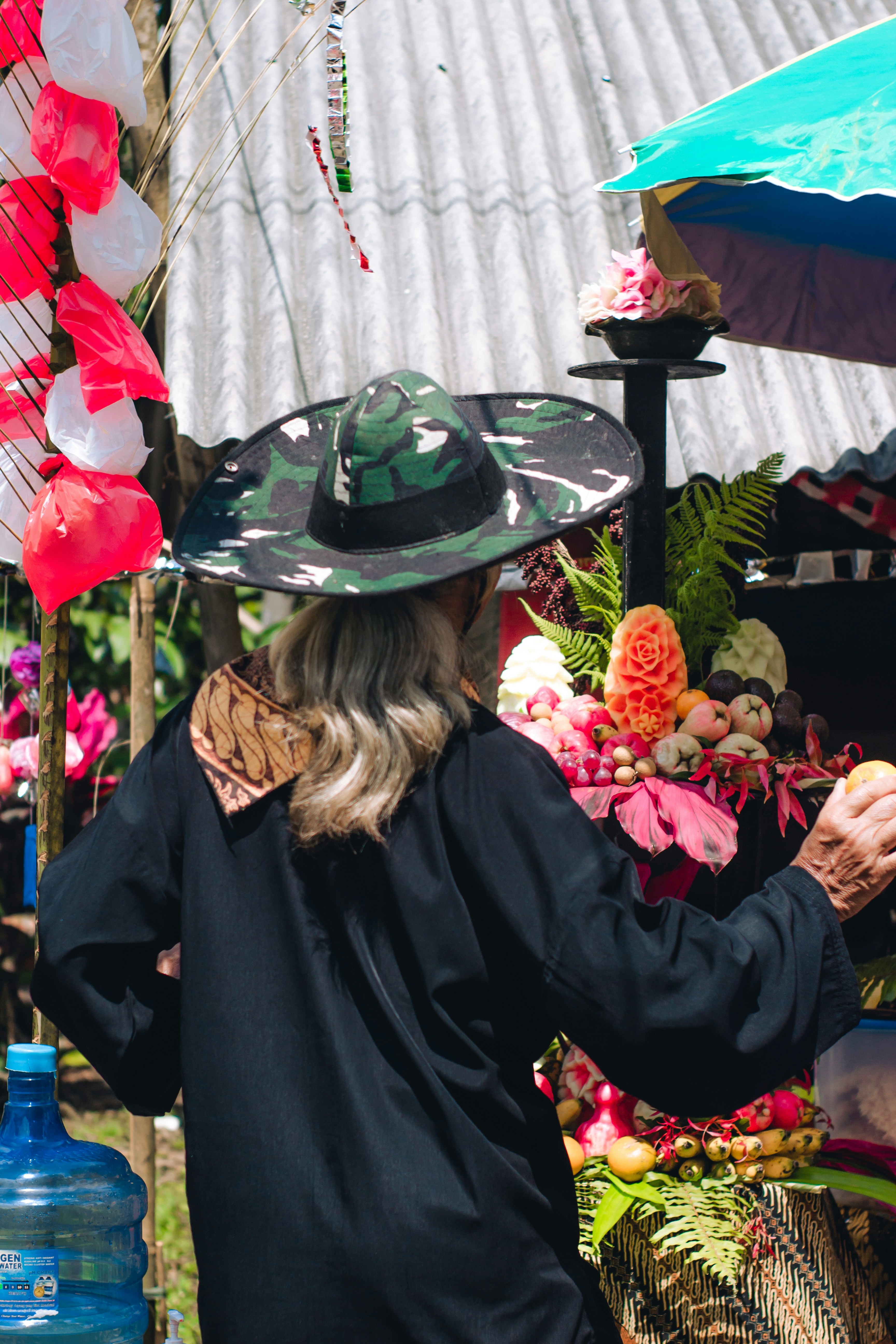 Back-Turned Vendor Under Camouflage Hat at a Lively Market Stall