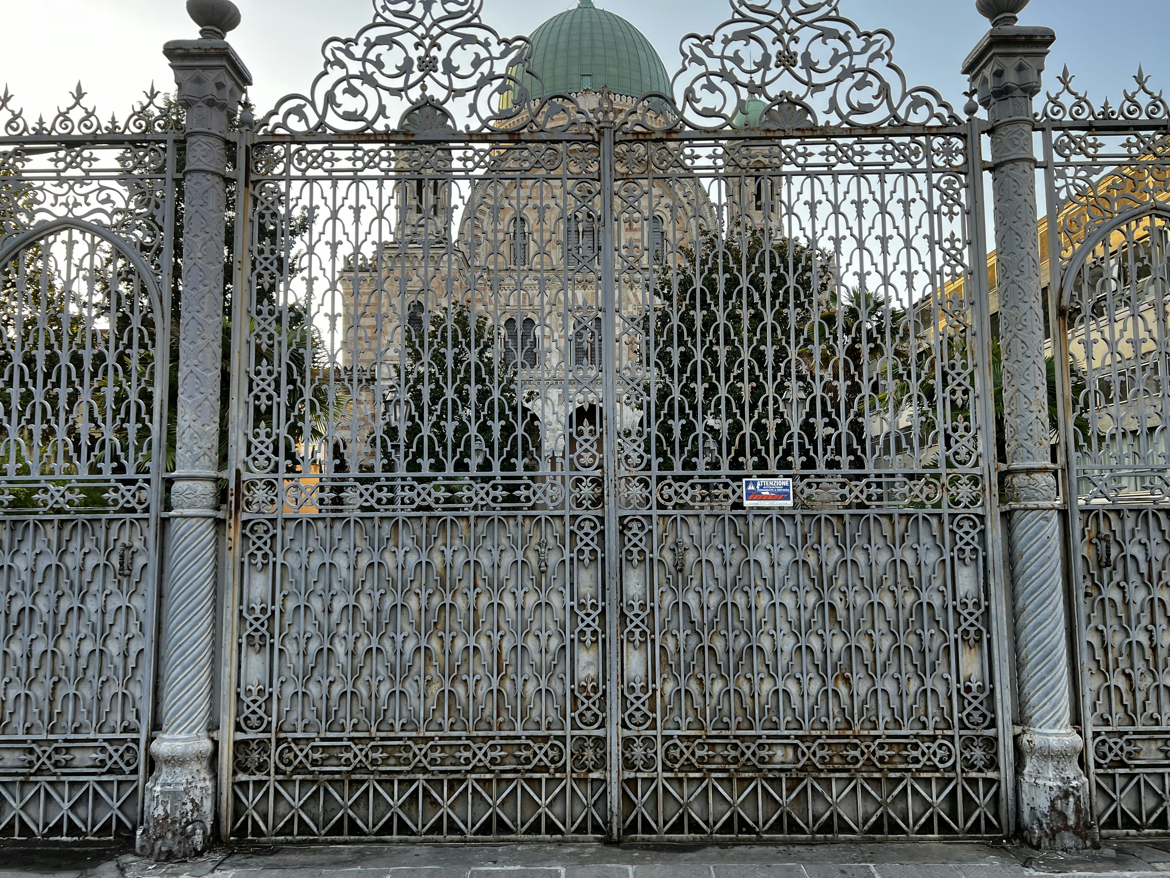 Iron Lace and a Dome: A Gate Framing a Historic Facade