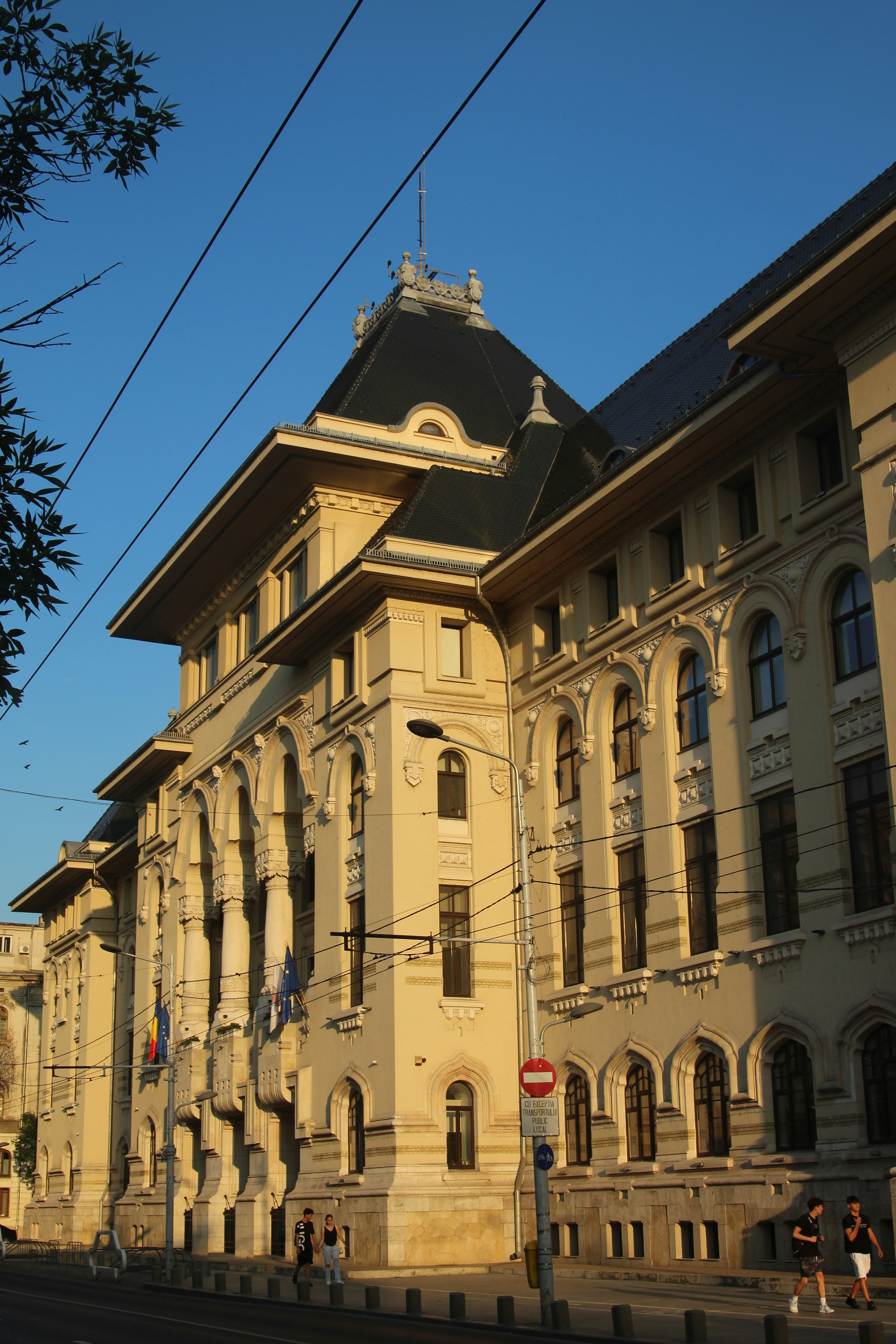Historic building featuring elegant arches and intricate details, illuminated by warm evening sunlight.