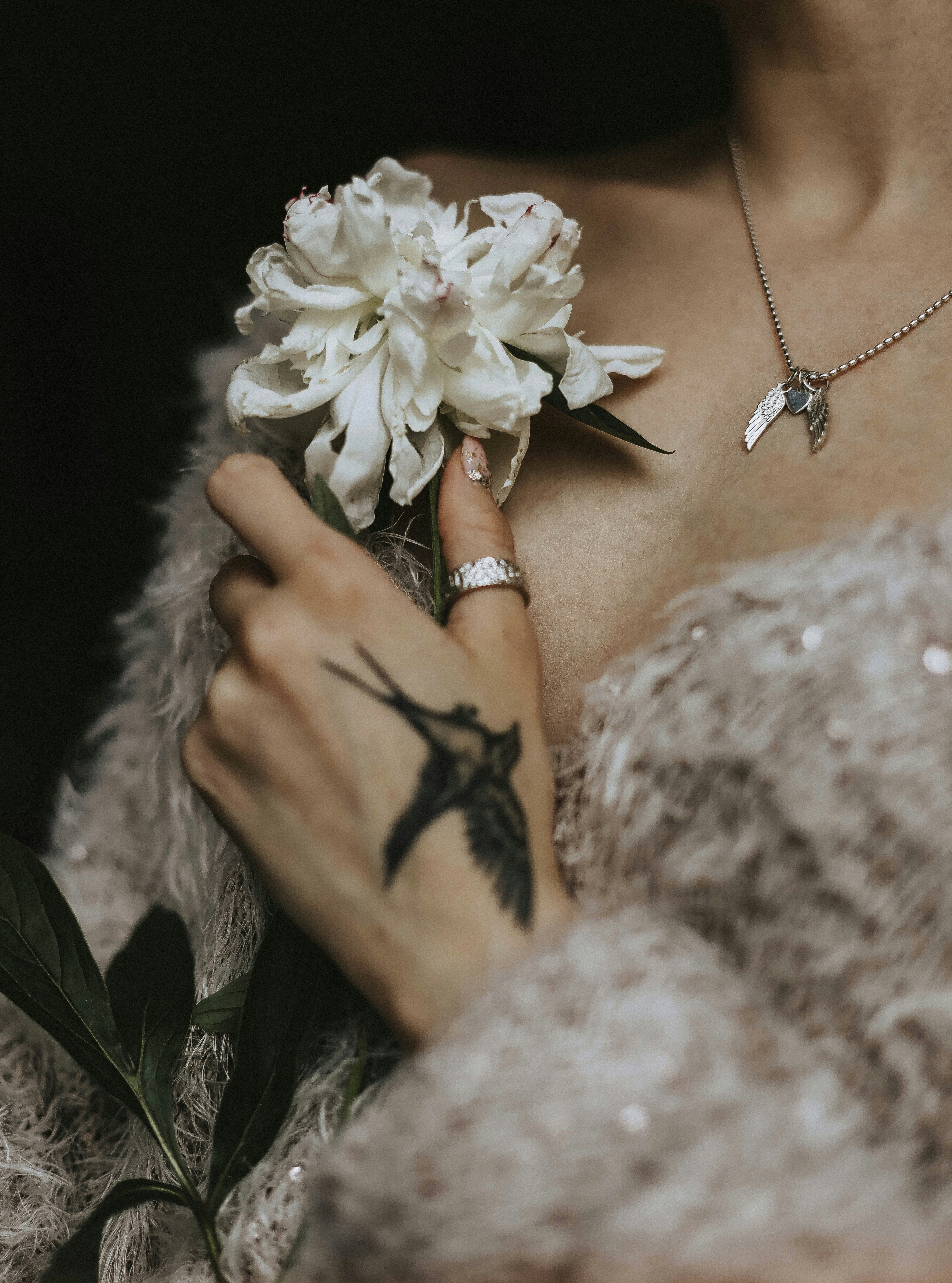 Ink and Ivory in Velvet Light: A bridal bouquet cradled by a tattooed hand