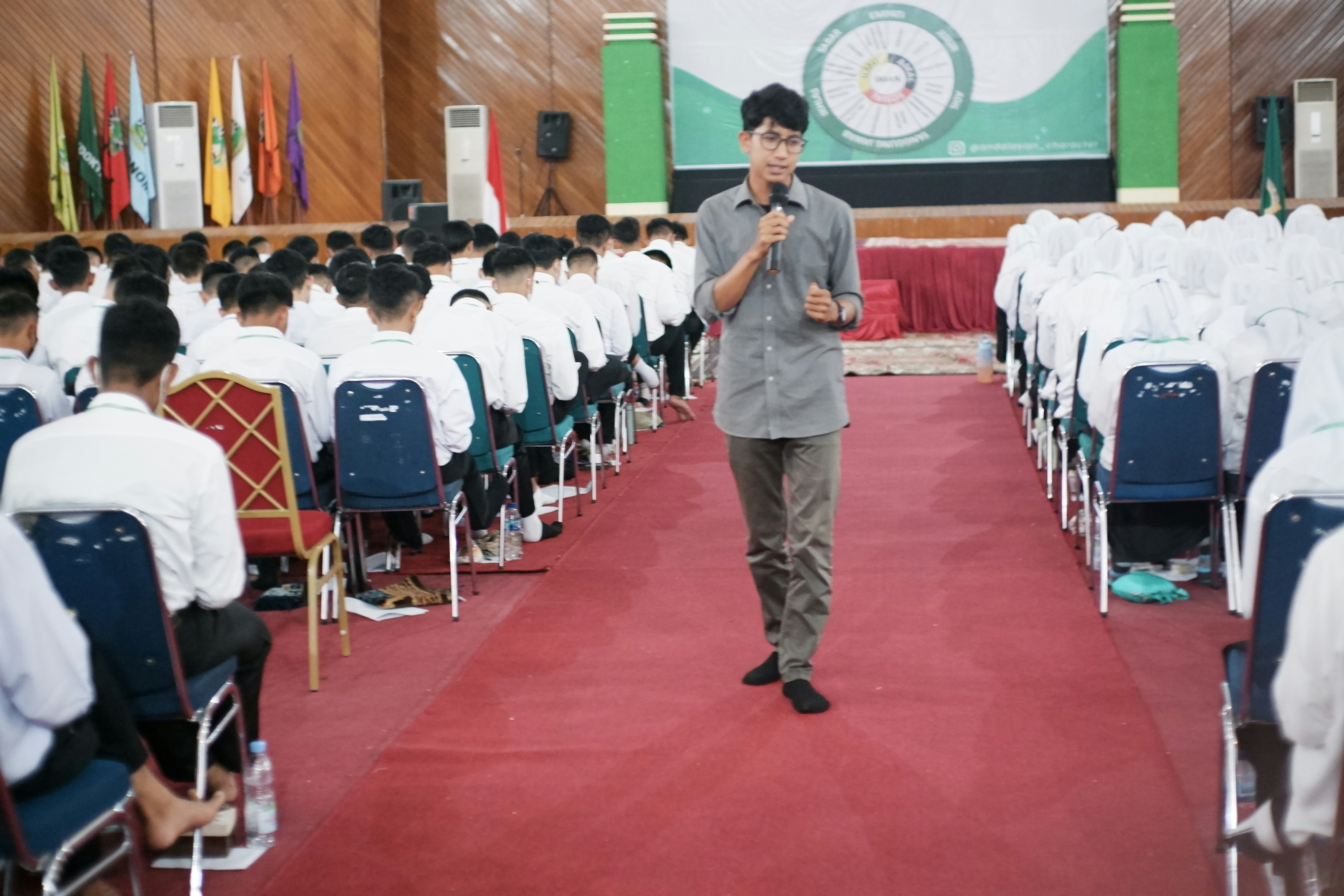 Una persona hablando por un micrófono frente a un grupo de personas ...
