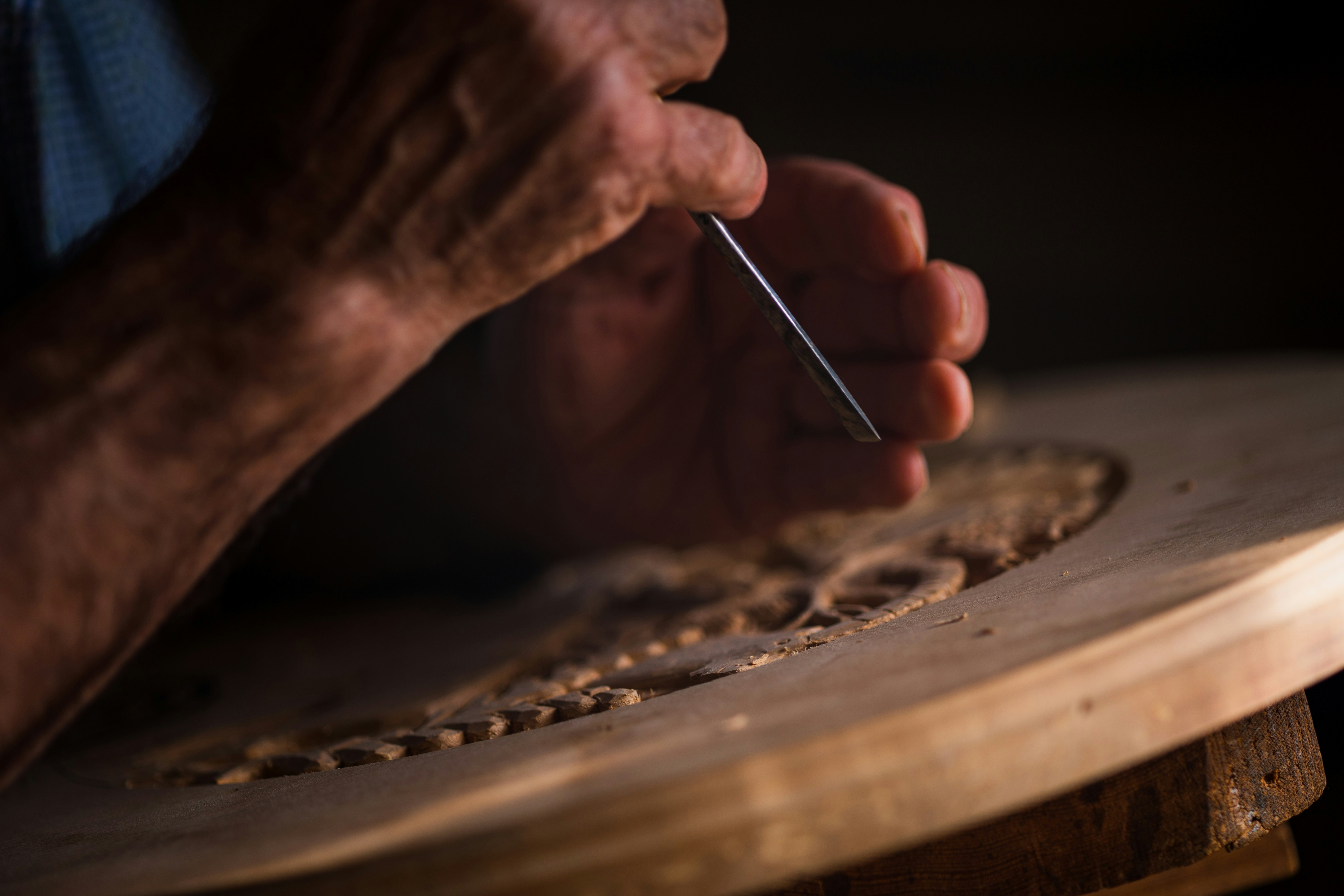 Hands skillfully carving intricate designs into a wooden surface, showcasing the dedication and artistry involved in woodworking.