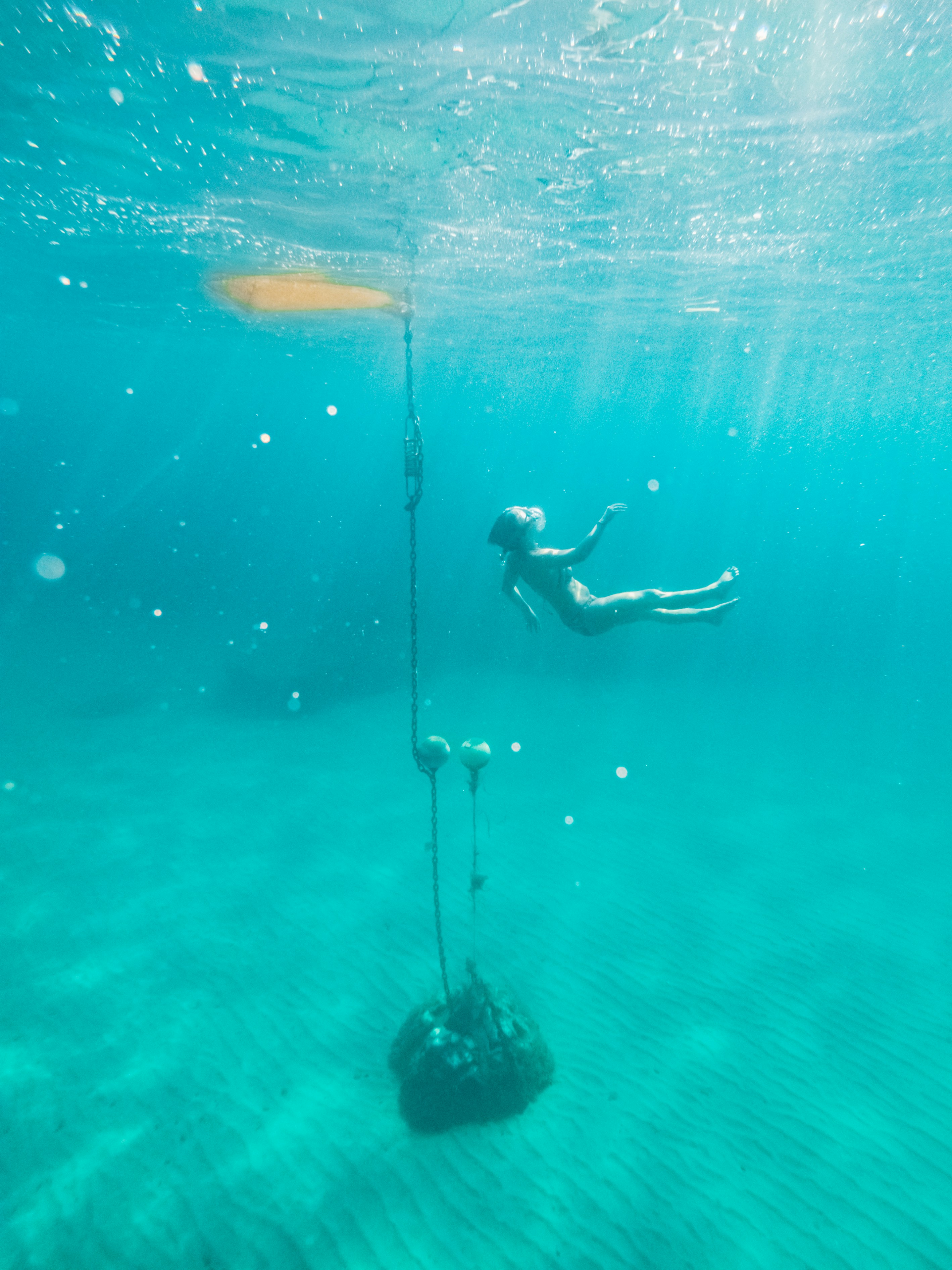Turquoise Drift: a swimmer gliding near a tethered buoy under sunlit water