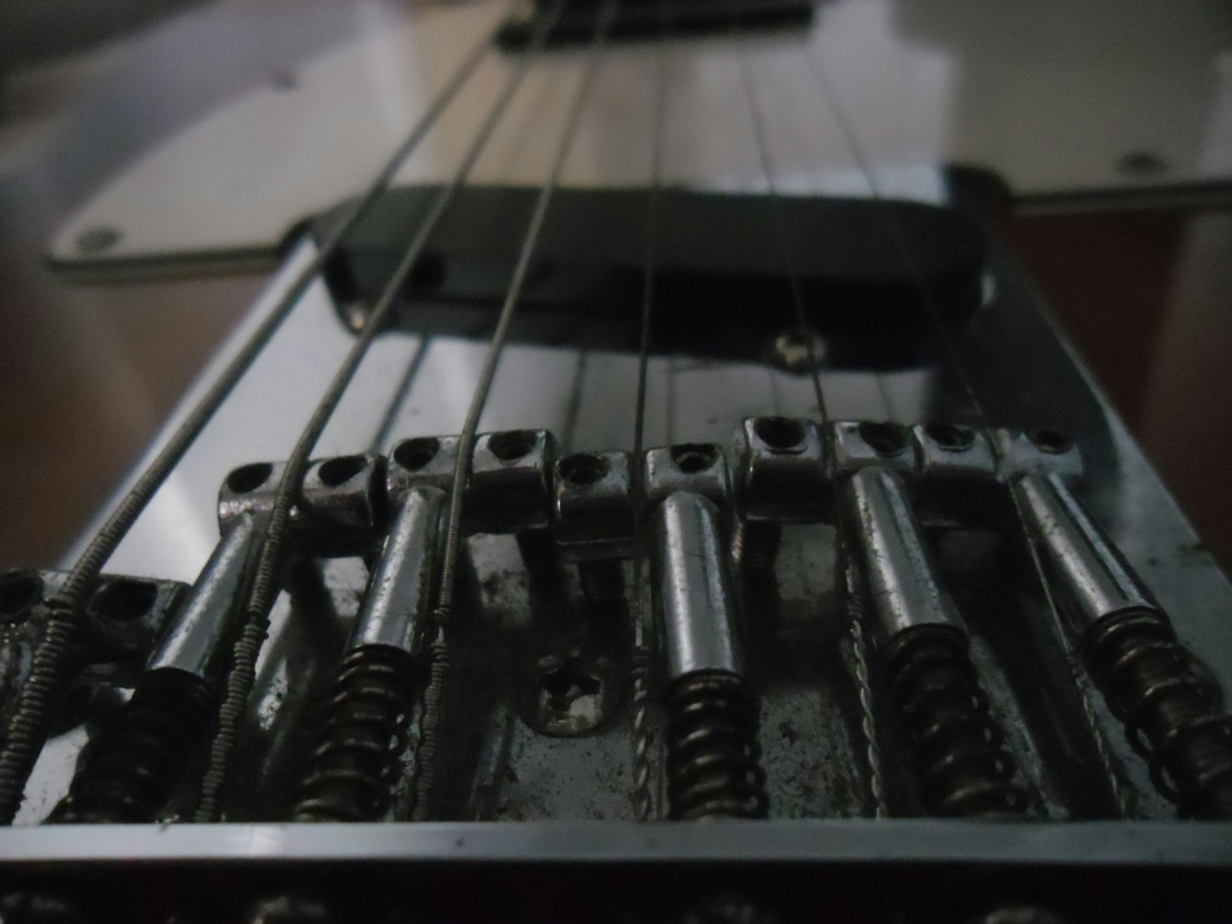 Close-up of a guitar bridge and strings, highlighting metal components and texture.