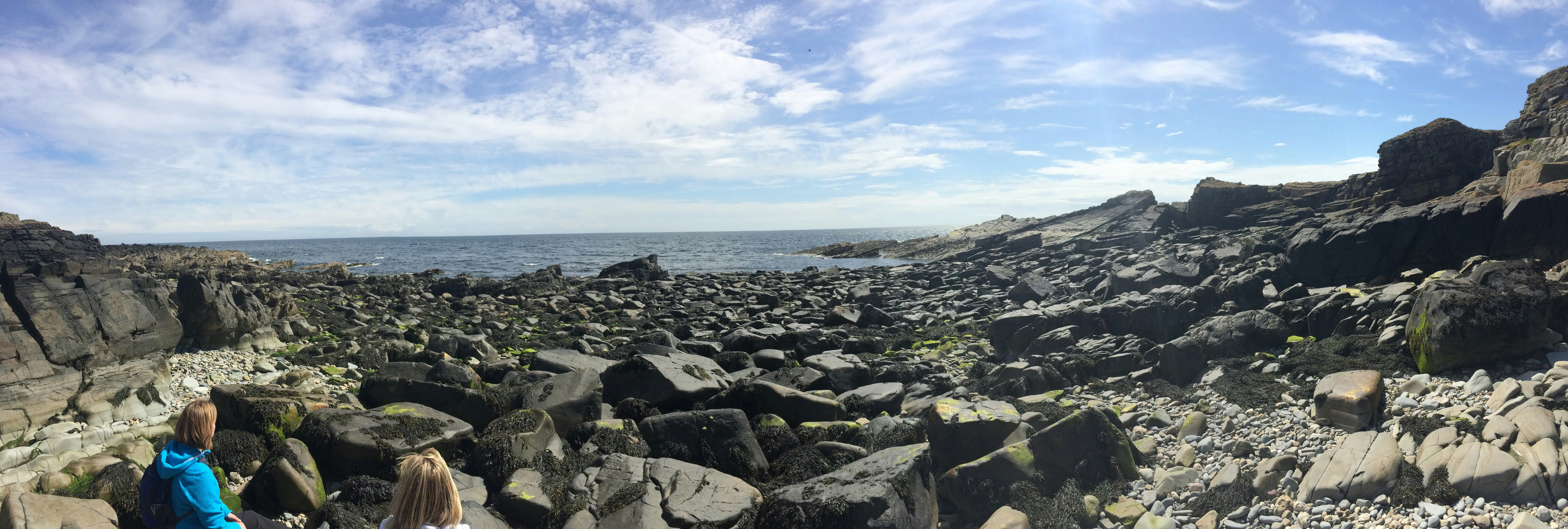 a rocky beach with people walking on it