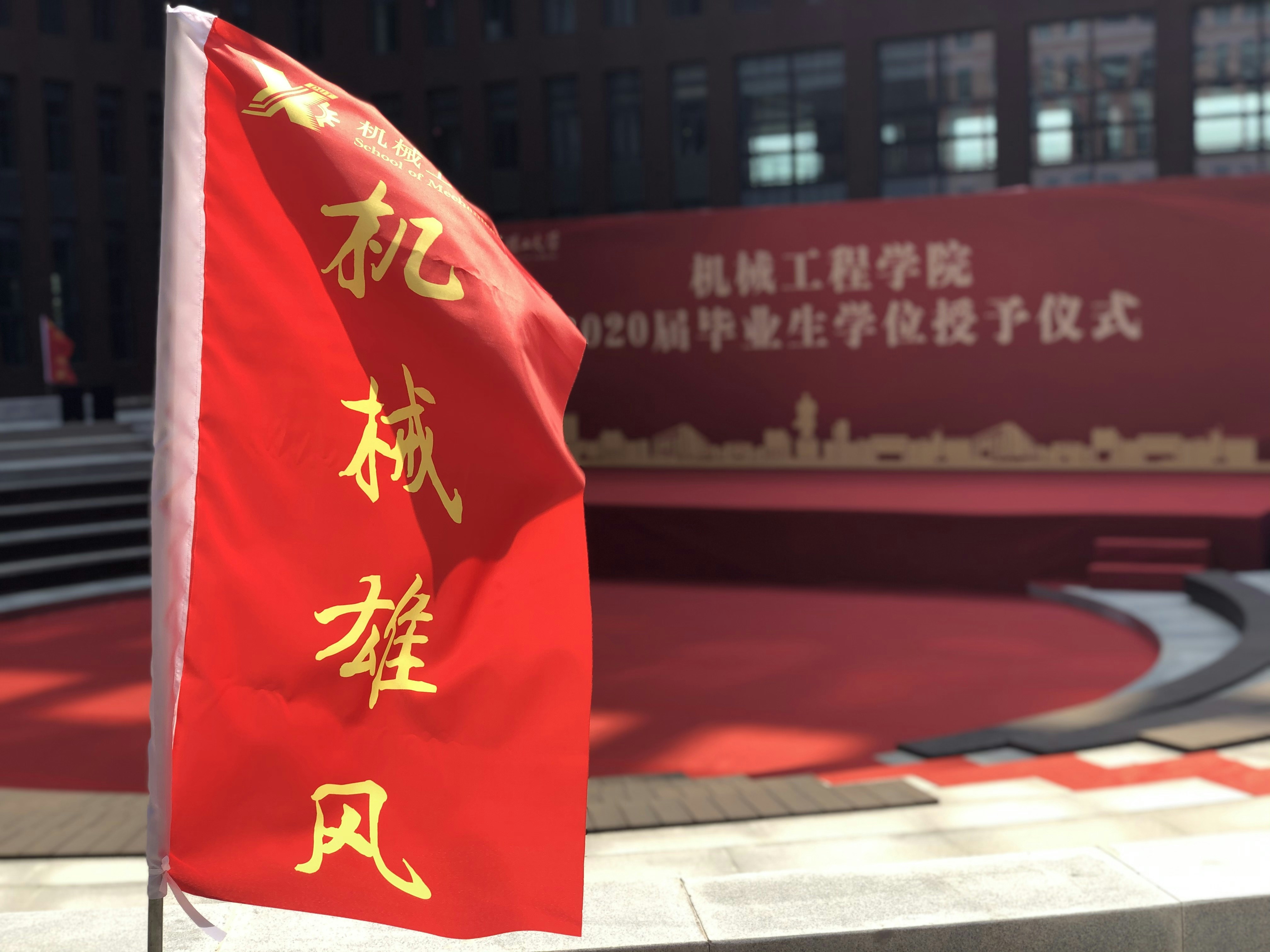 Crimson Banner at the Edge of a Campus Ceremony Stage