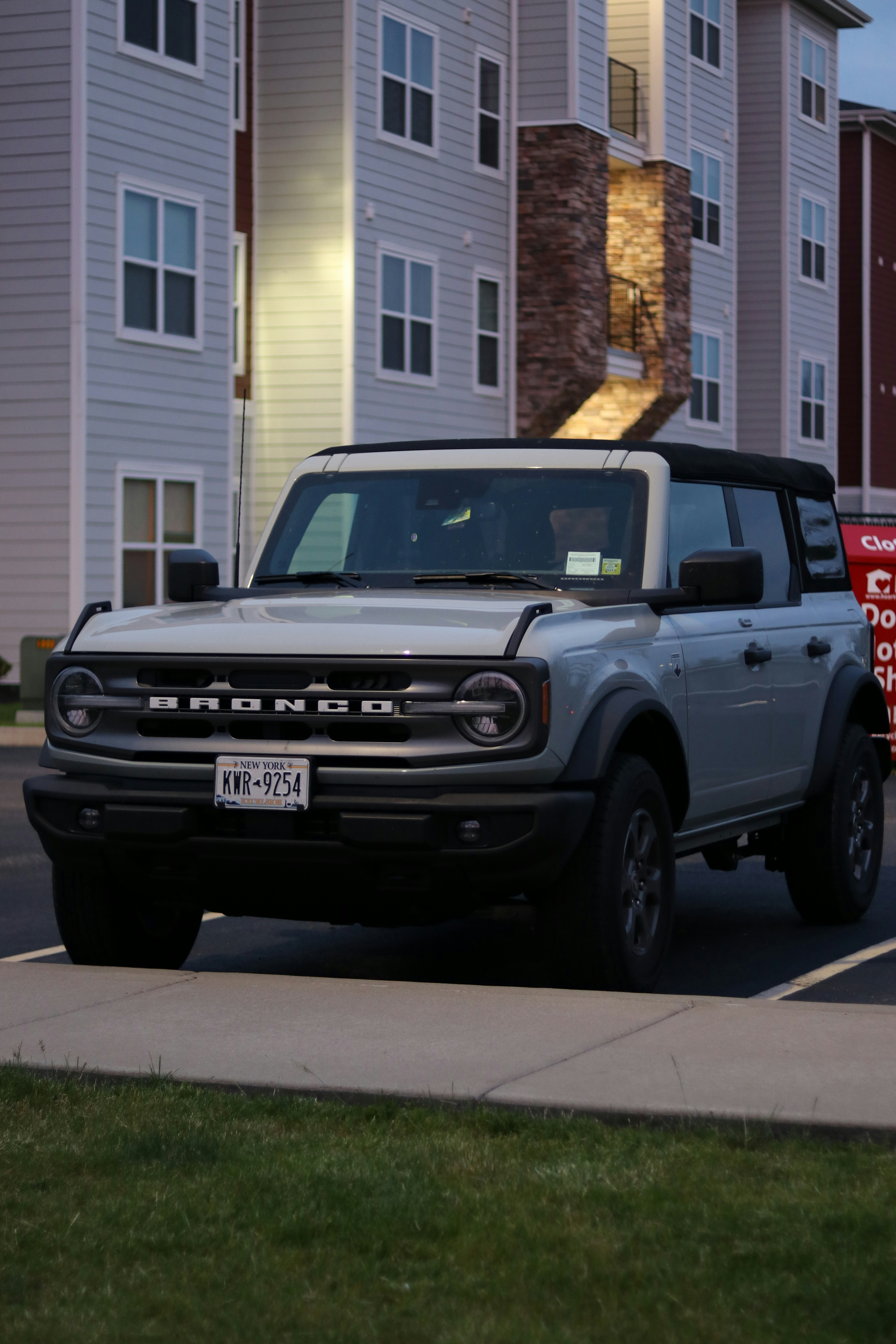 Bronco in the Quiet Dusk: A White SUV Framed by Pastel Apartment Row