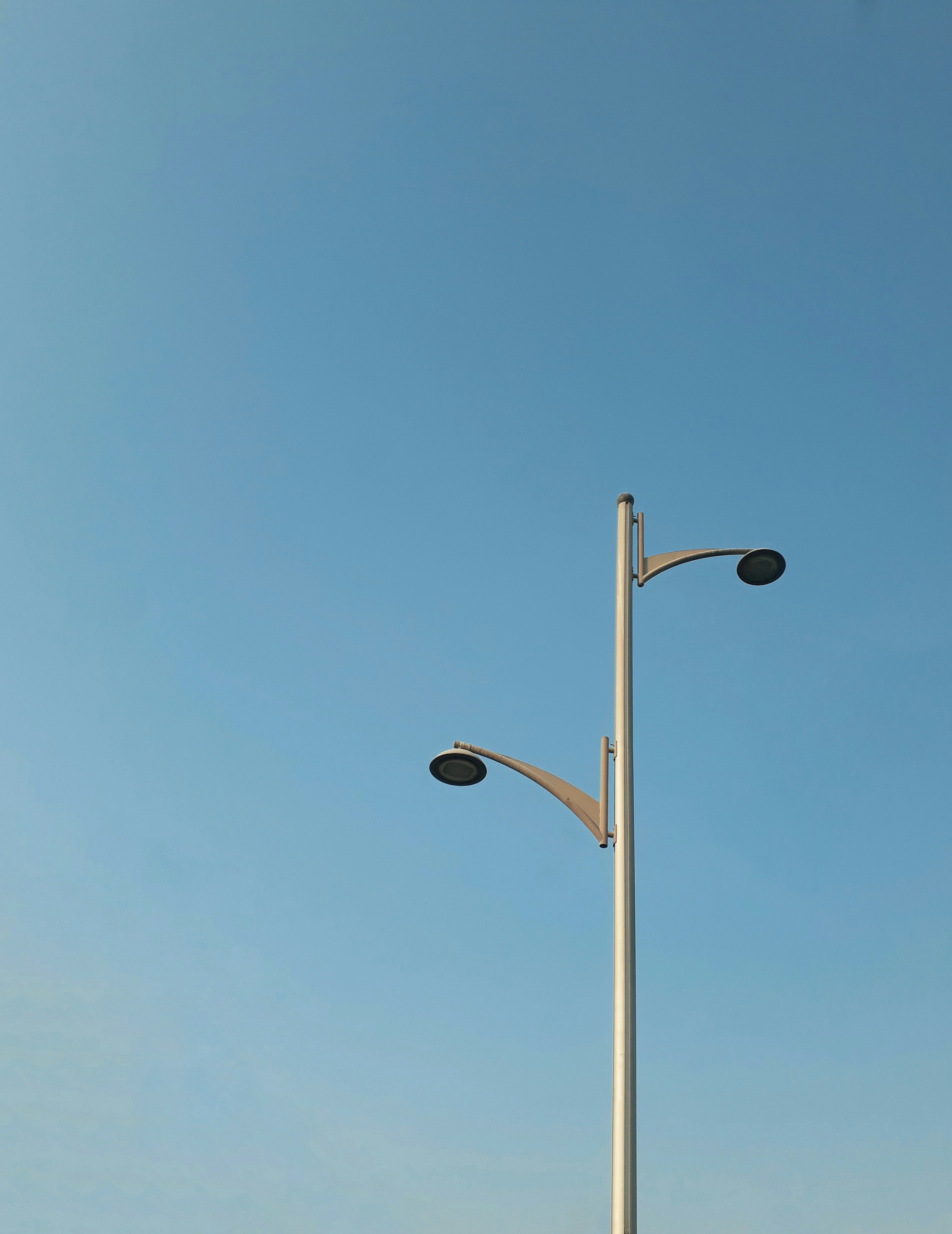 Minimalist street lamp against a clear blue sky, showcasing modern design and functionality.